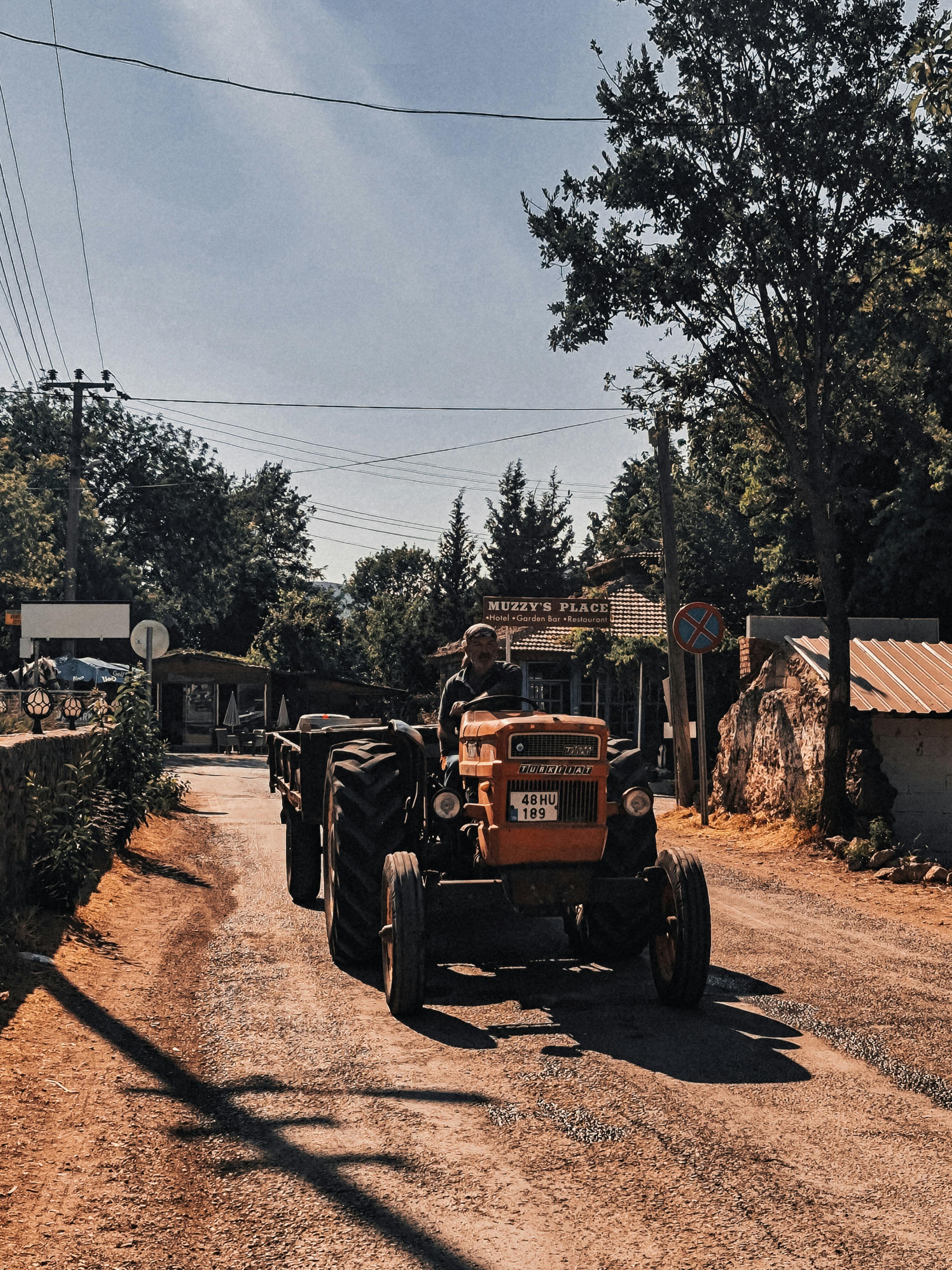 Man Driving a Tractor on Unpaved Road · Free Stock Photo
