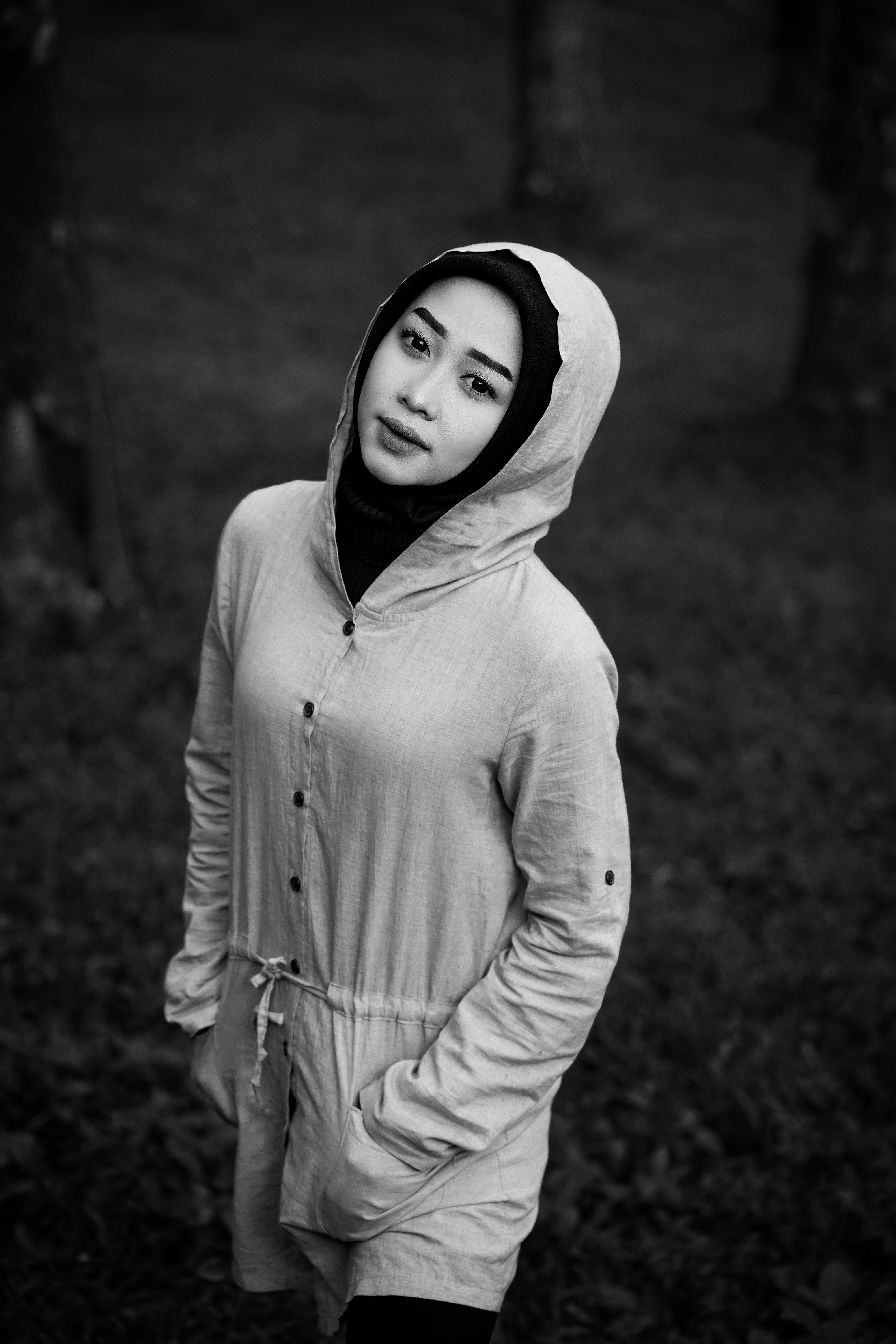 Woman in Hoodie Standing on Grass Field in Grayscale Photography · Free Stock Photo