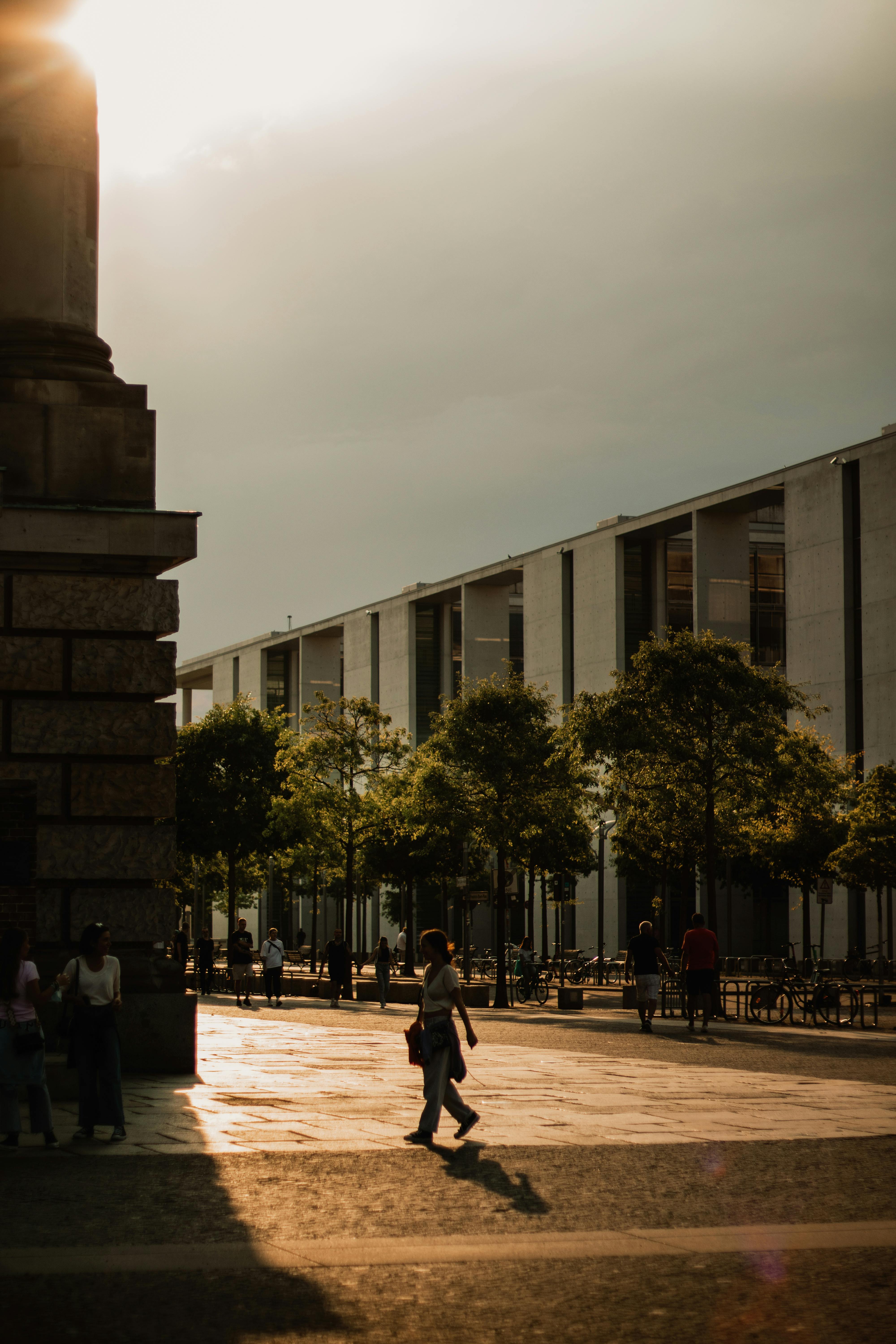 Woman Walking across Town Square at Sunset · Free Stock Photo