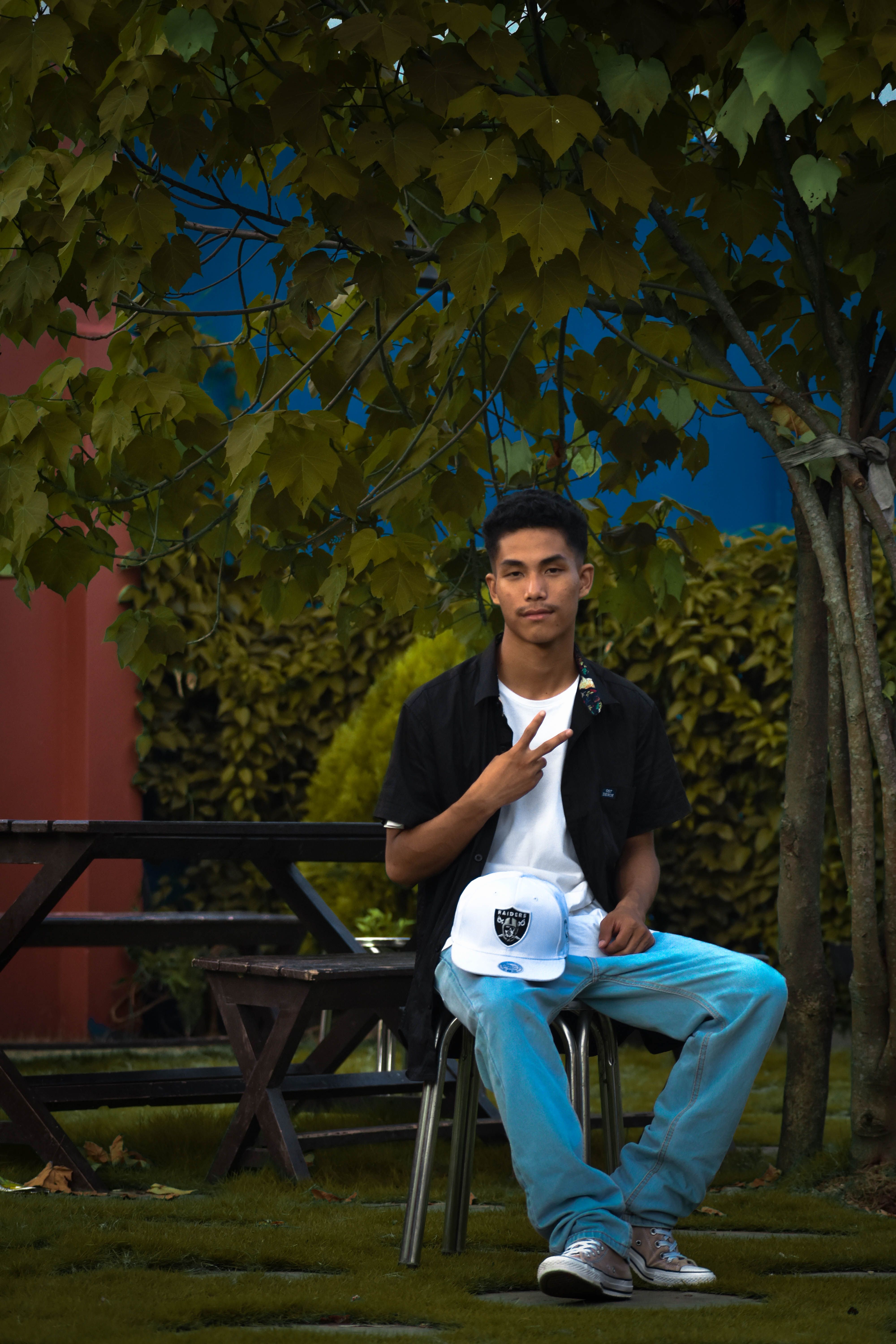 A Man Sitting on a Chair Making a Peace Sign · Free Stock Photo