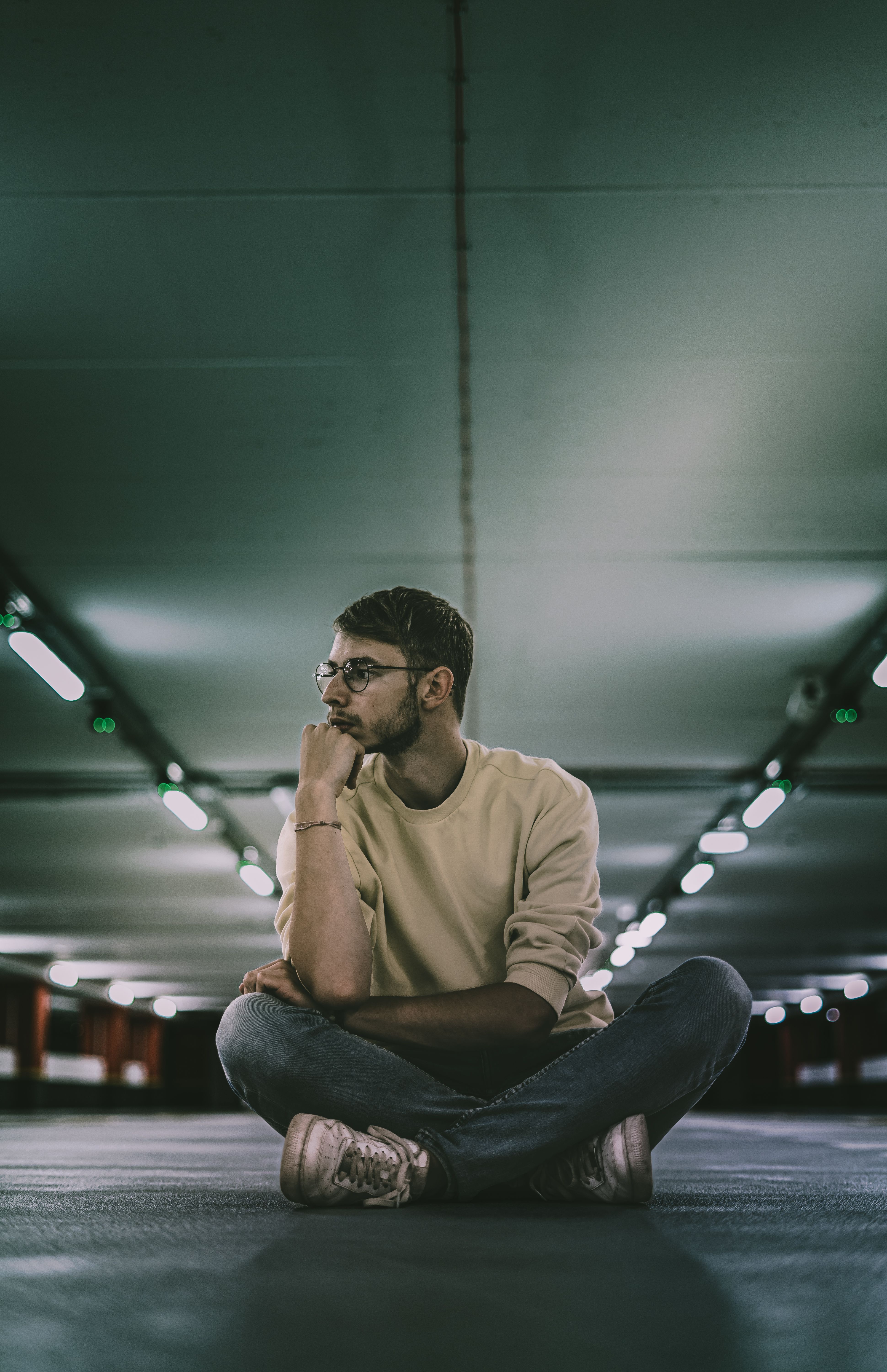 Man Sitting Cross-Legged Barefoot by a Concrete Wall · Free Stock Photo