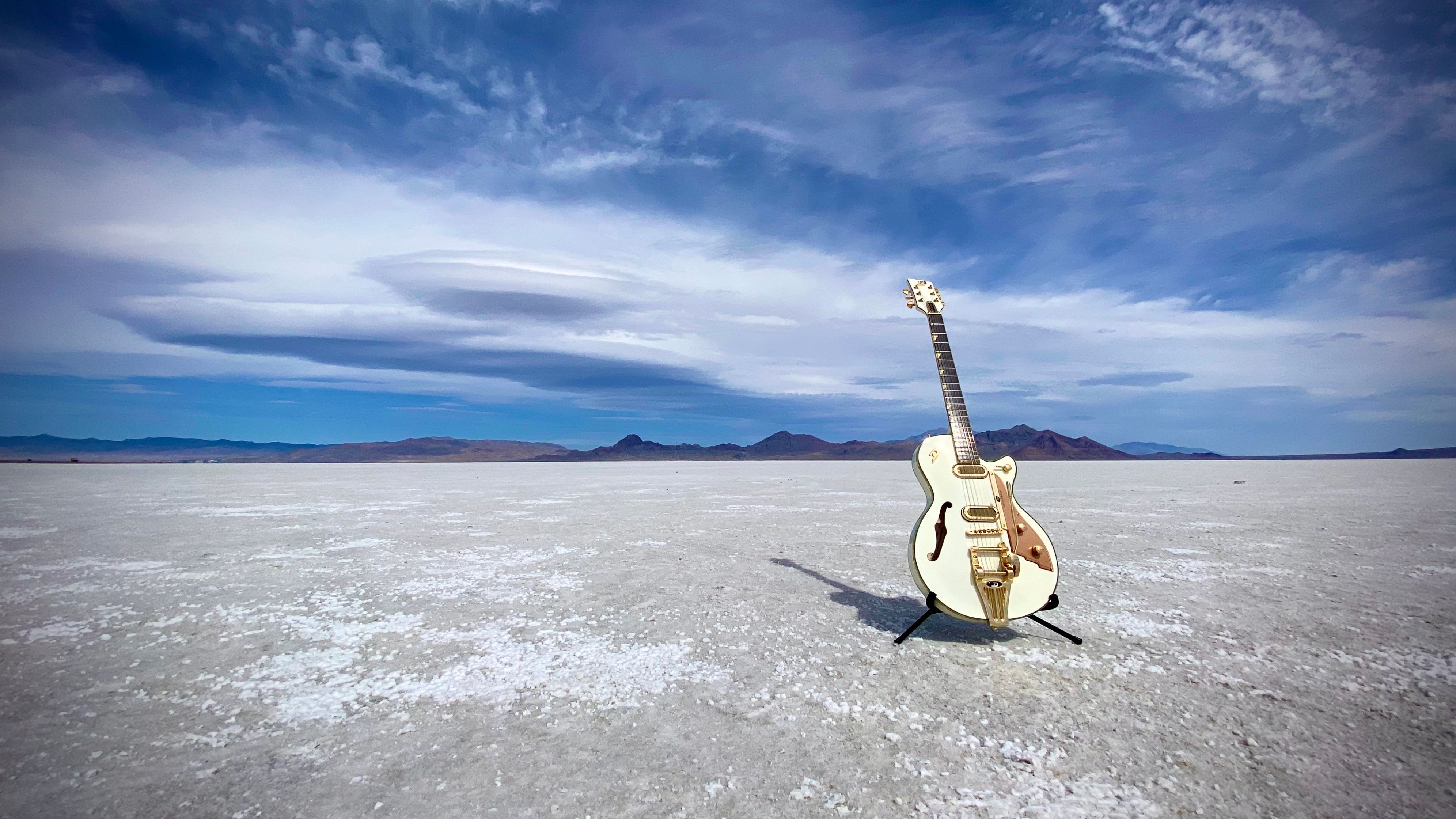 An Expensive Guitar on the Sandy Shore Under Blue Sky · Free Stock Photo