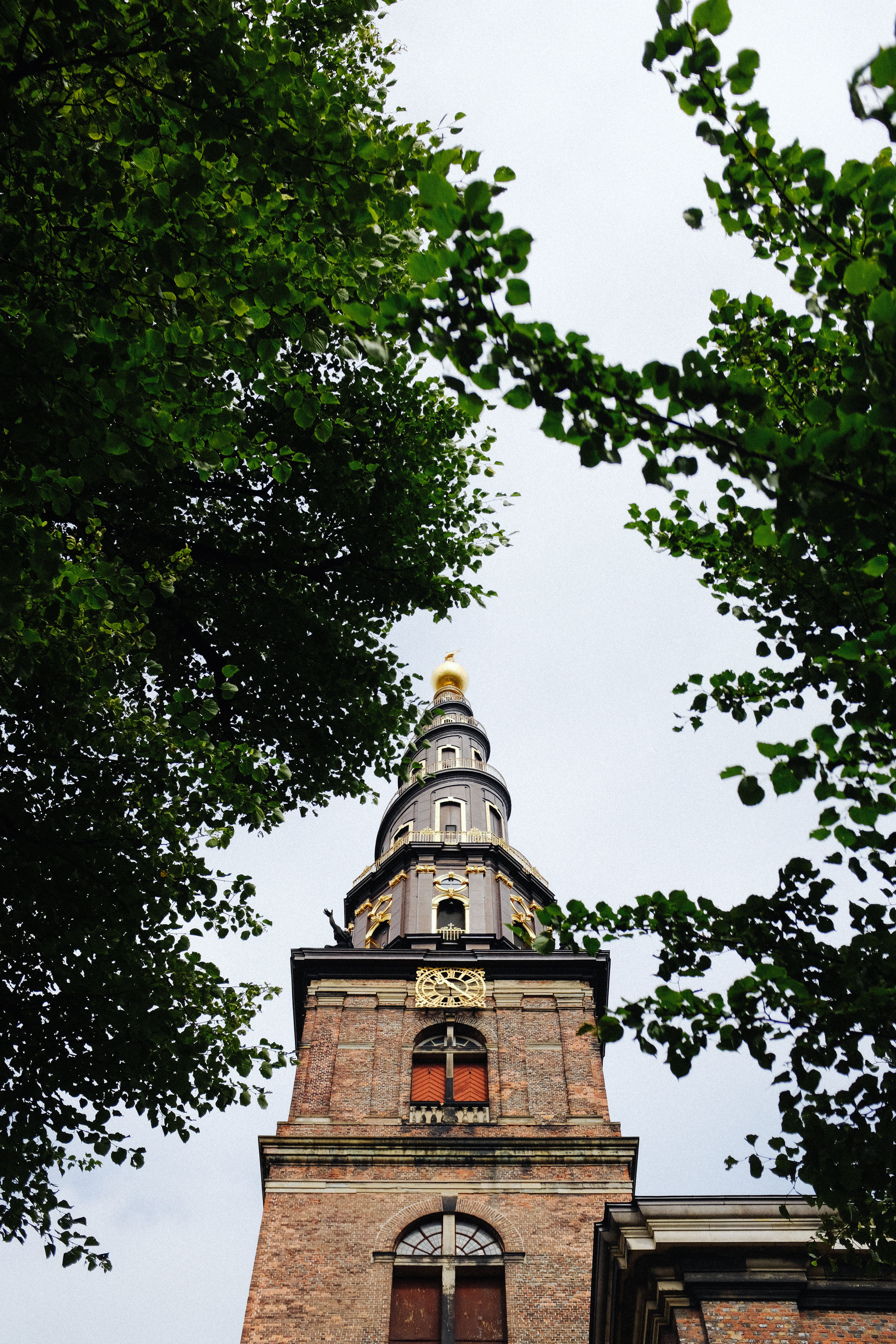 Old Church Tower in Green Trees against Blue Sky · Free Stock Photo