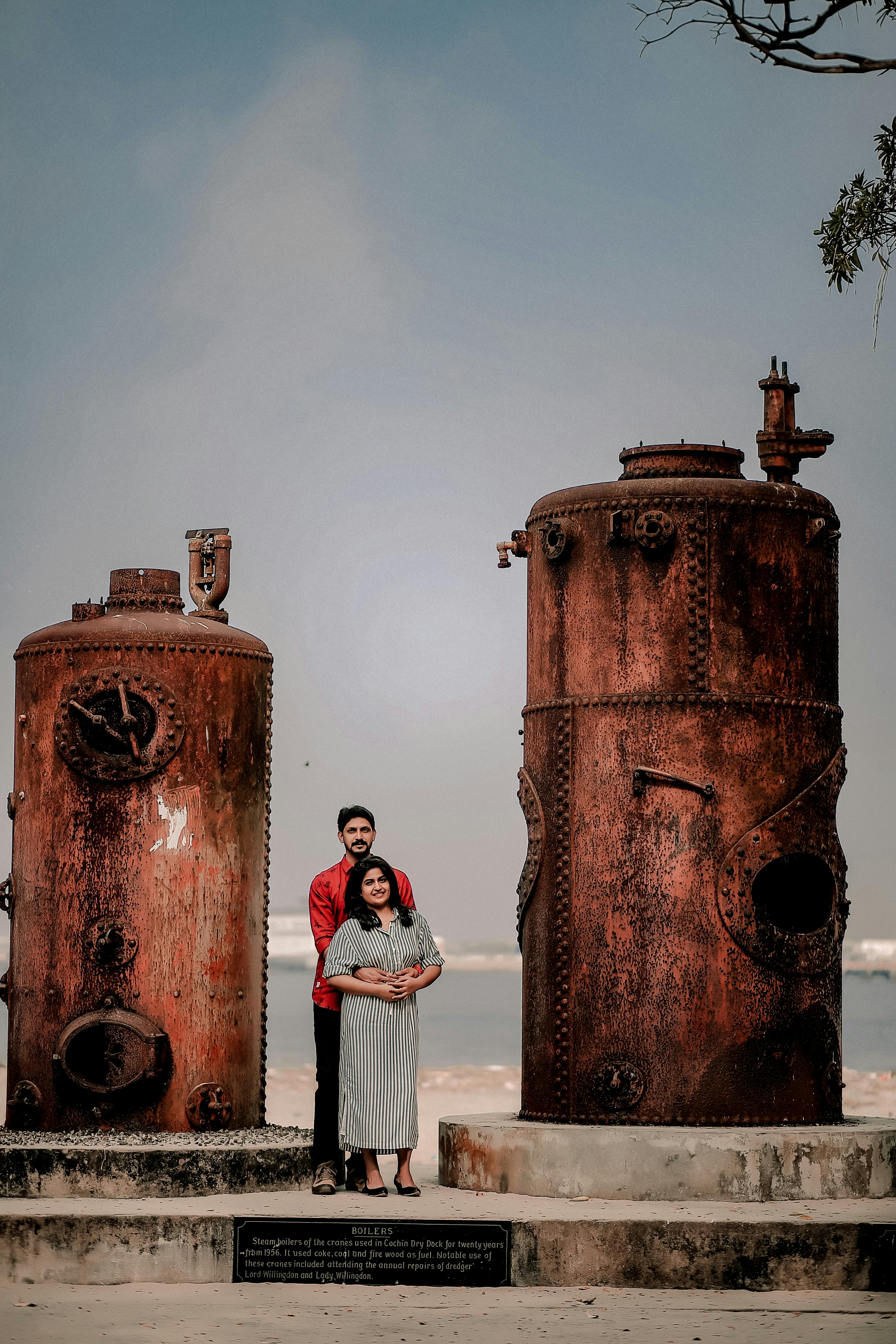 A Romantic Couple Standing beside Tanks near the Sea · Free Stock Photo