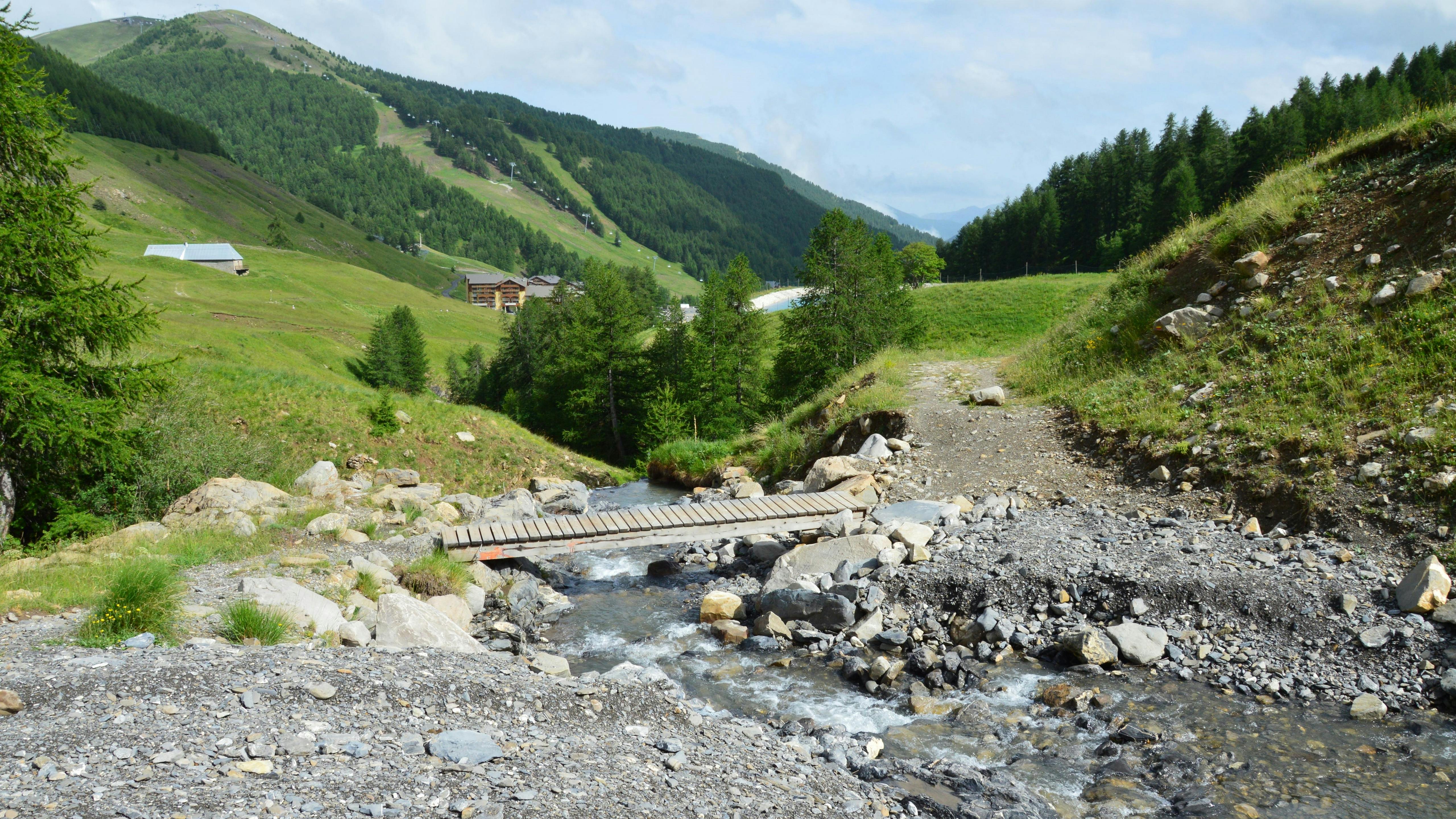 Scenic Mountain Stream with Wooden Bridge · Free Stock Photo