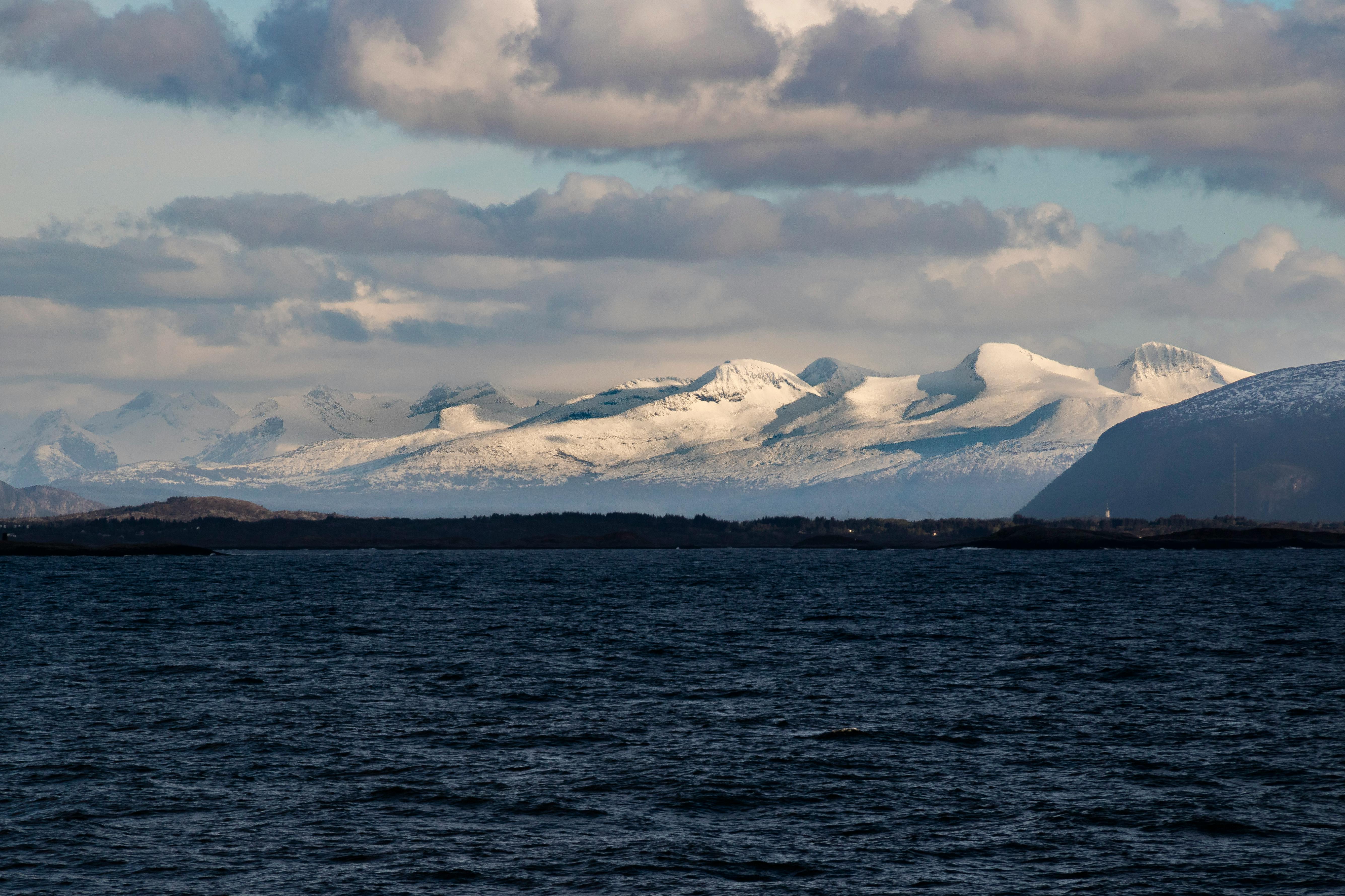Snow-Covered Mountains near Ocean under the Cloudy Sky · Free Stock Photo