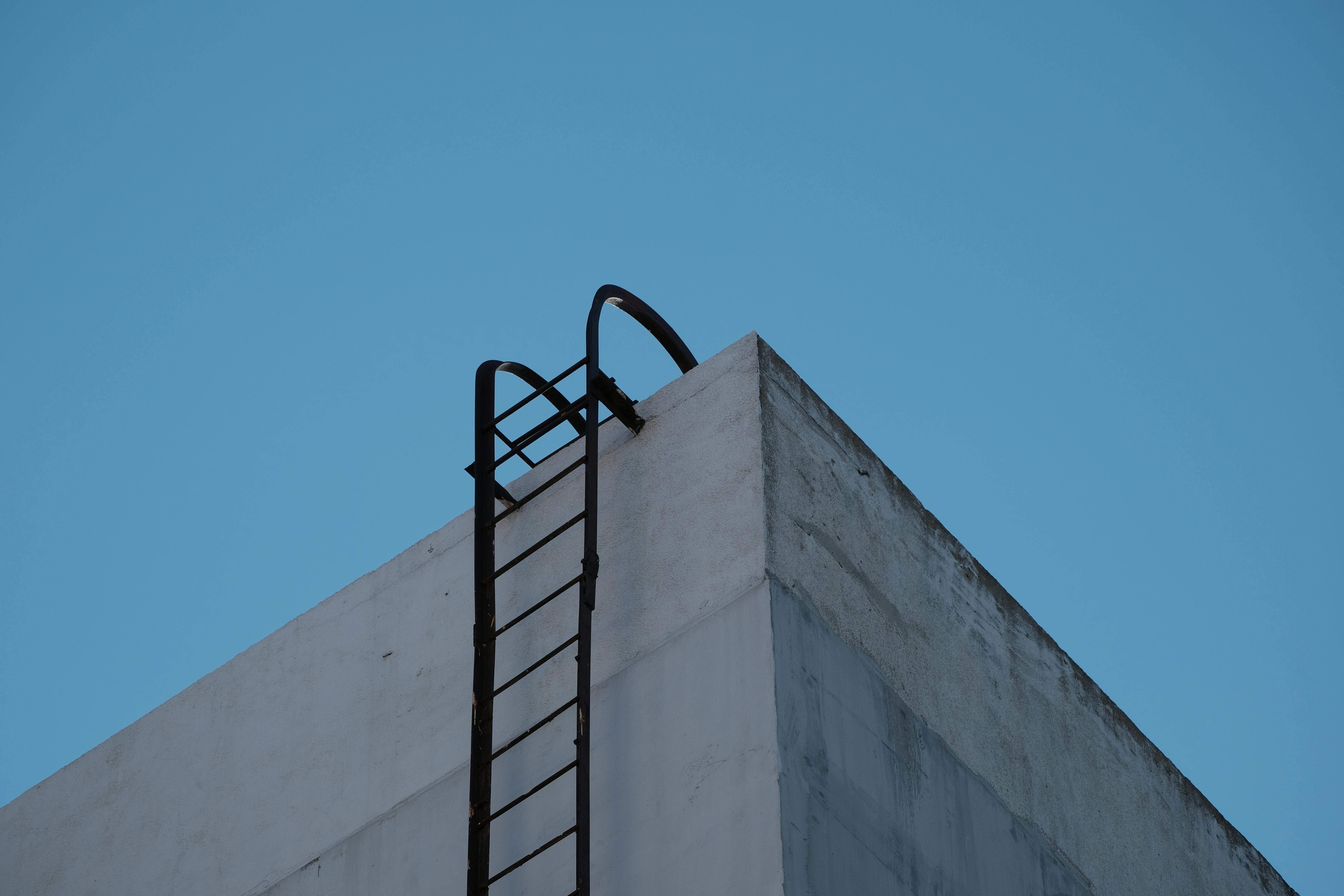 Black Metal Ladder Mounted on the Concrete Wall · Free Stock Photo