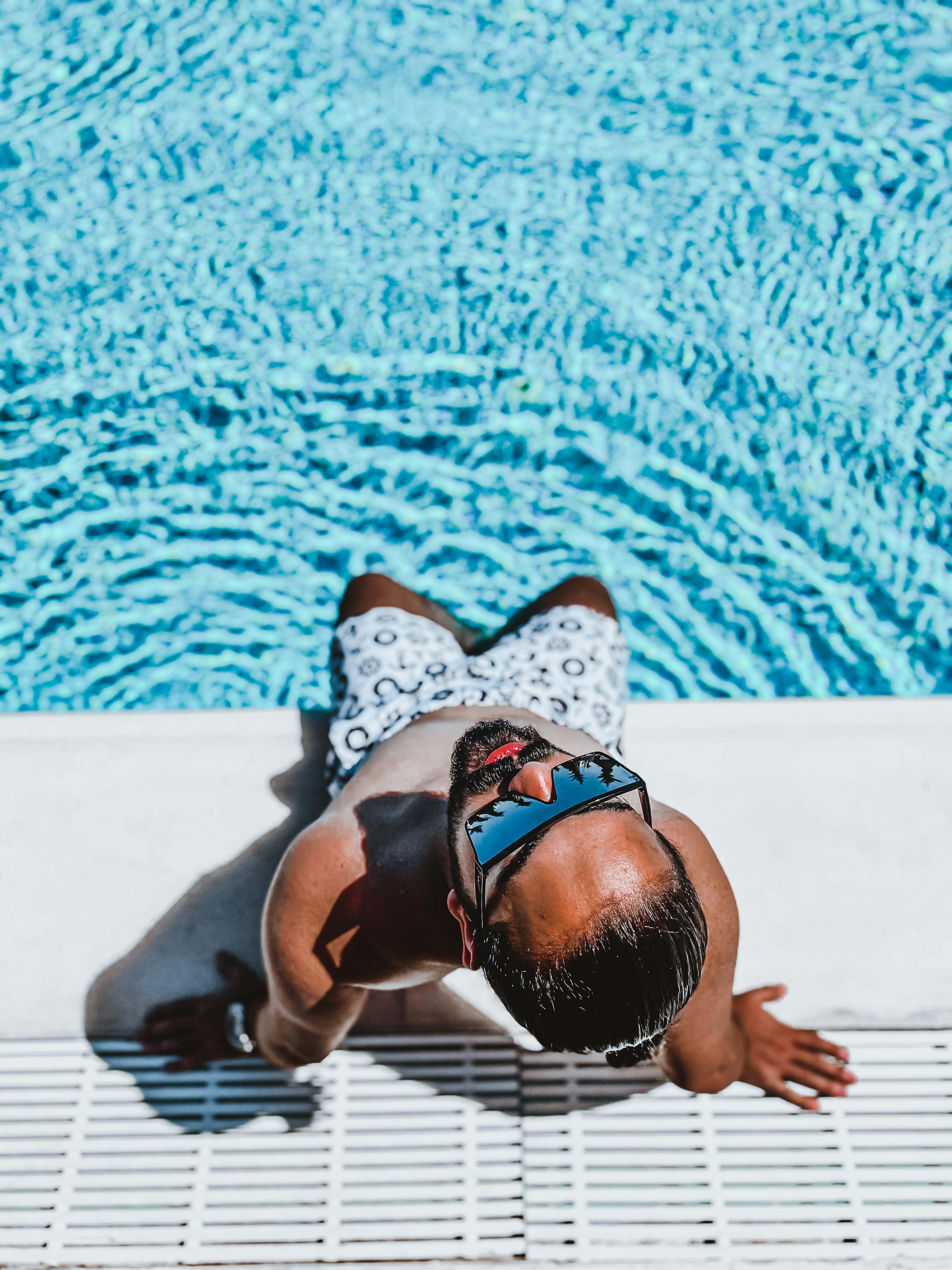 A Man Sitting by the Swimming Pool · Free Stock Photo