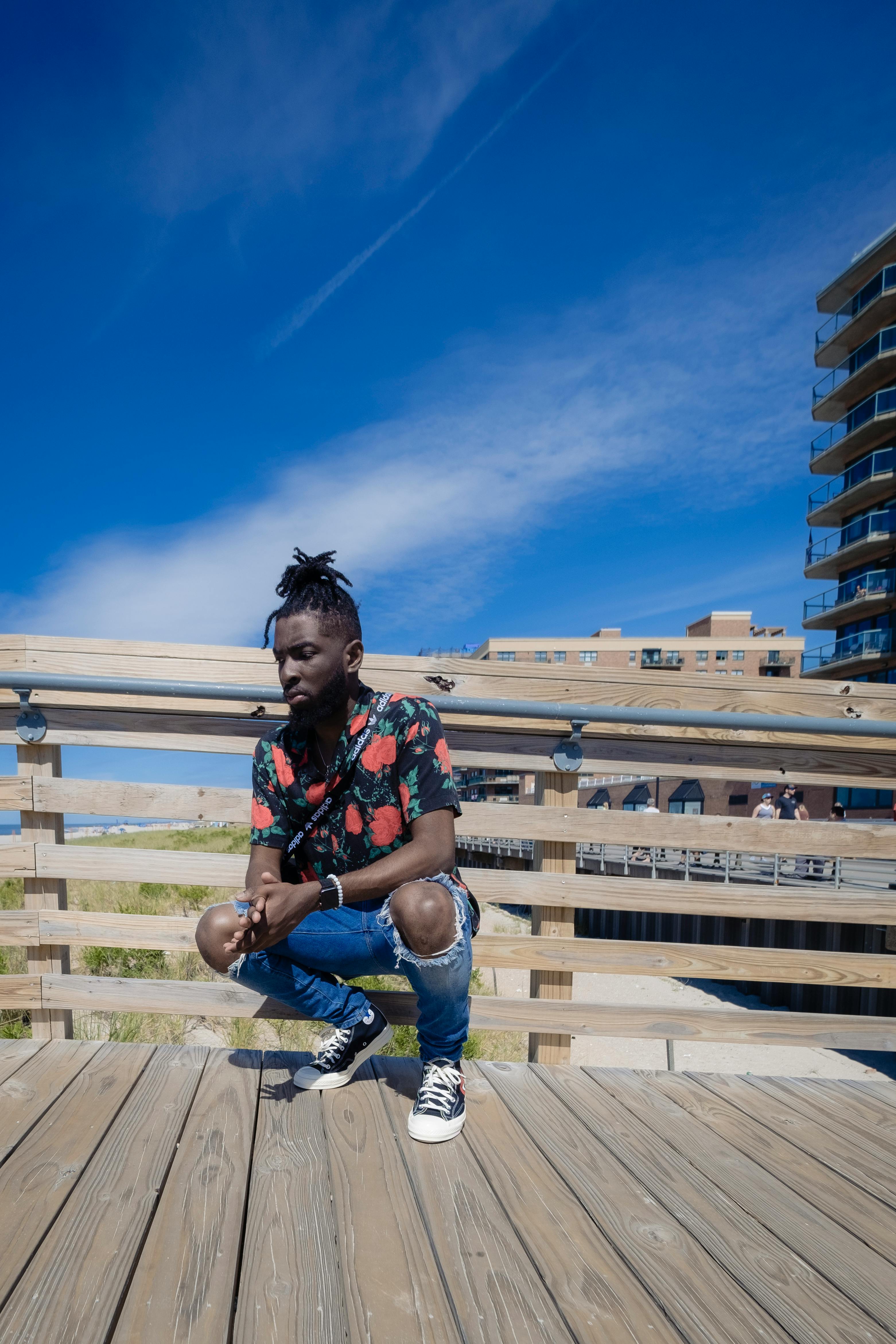 A Man in Printed Shirt Sitting on a Wooden Bridge with His Hands ...
