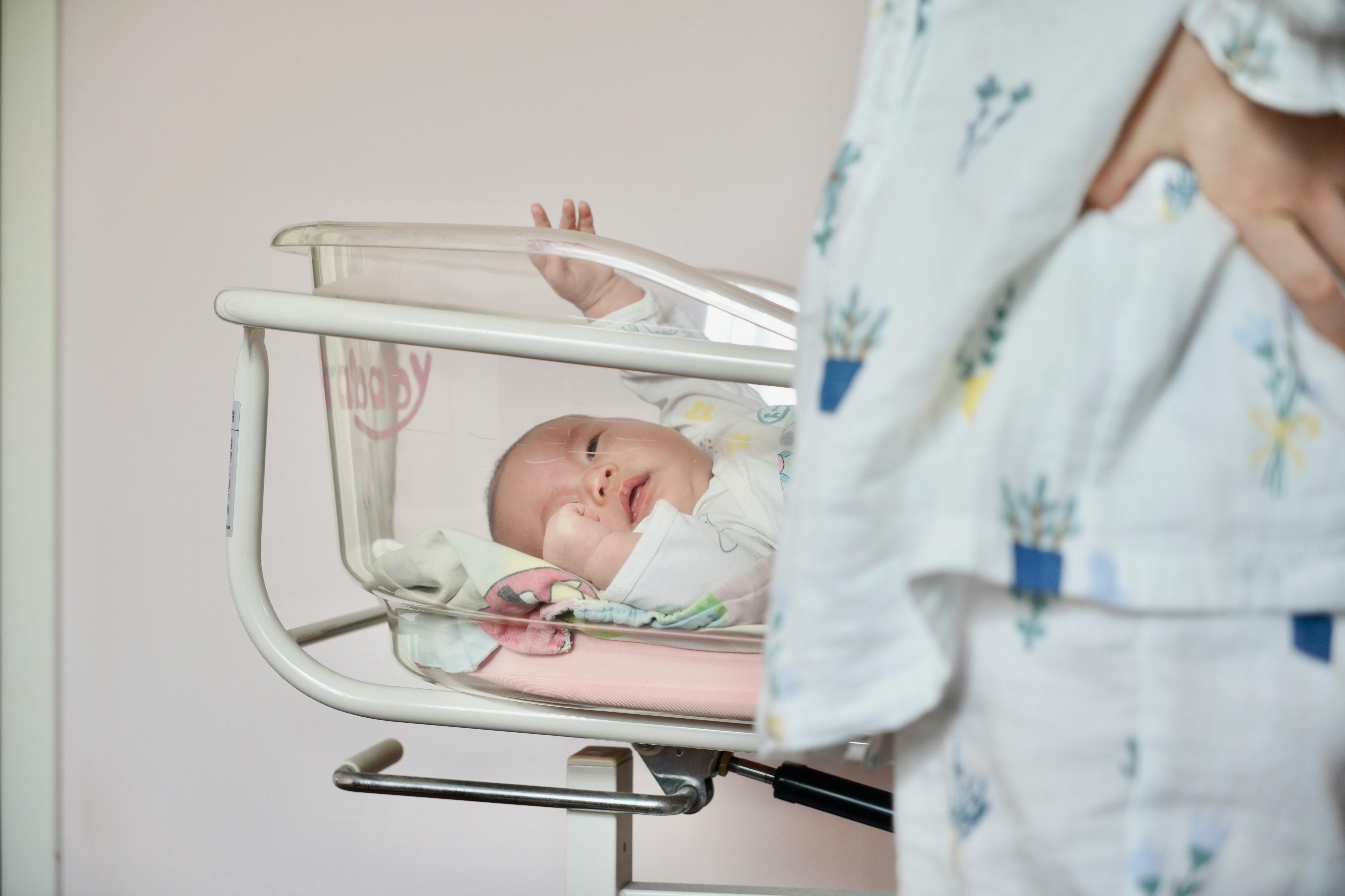 A Newborn Baby Lying in a Hospital Infant Bassinet · Free Stock Photo