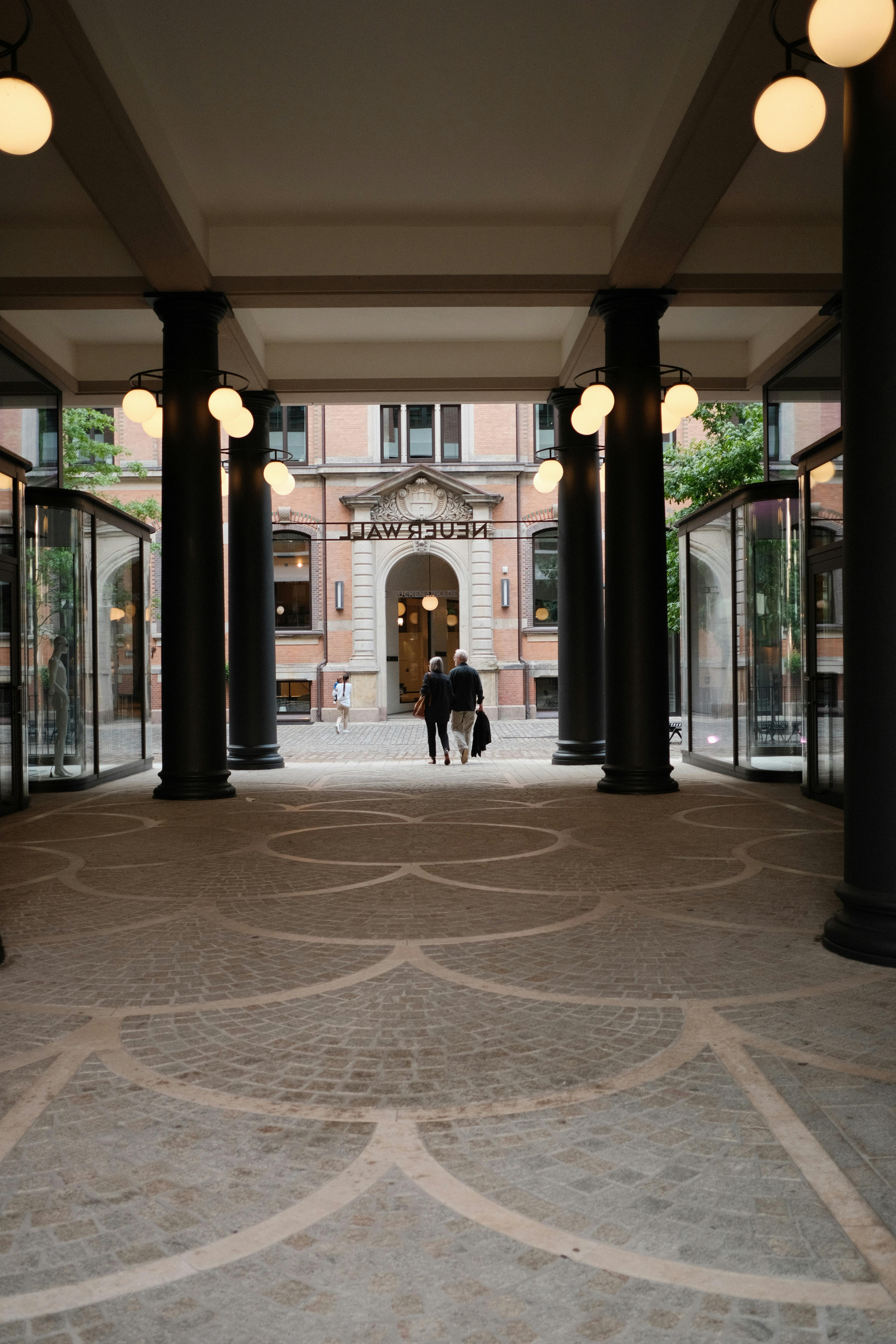 People Walking on Hallway Between Pillars · Free Stock Photo