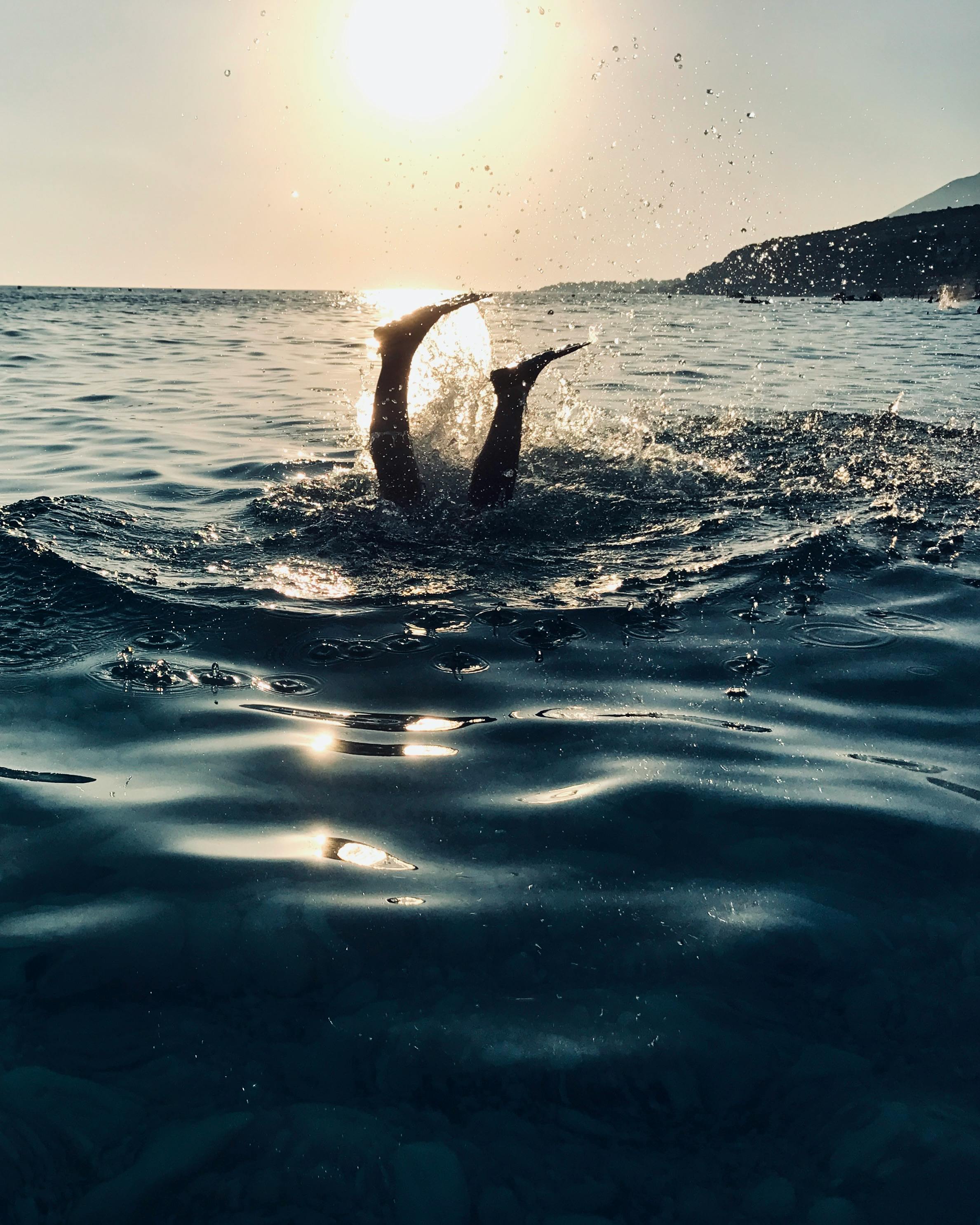 Person Swimming in the Ocean During Sunset · Free Stock Photo