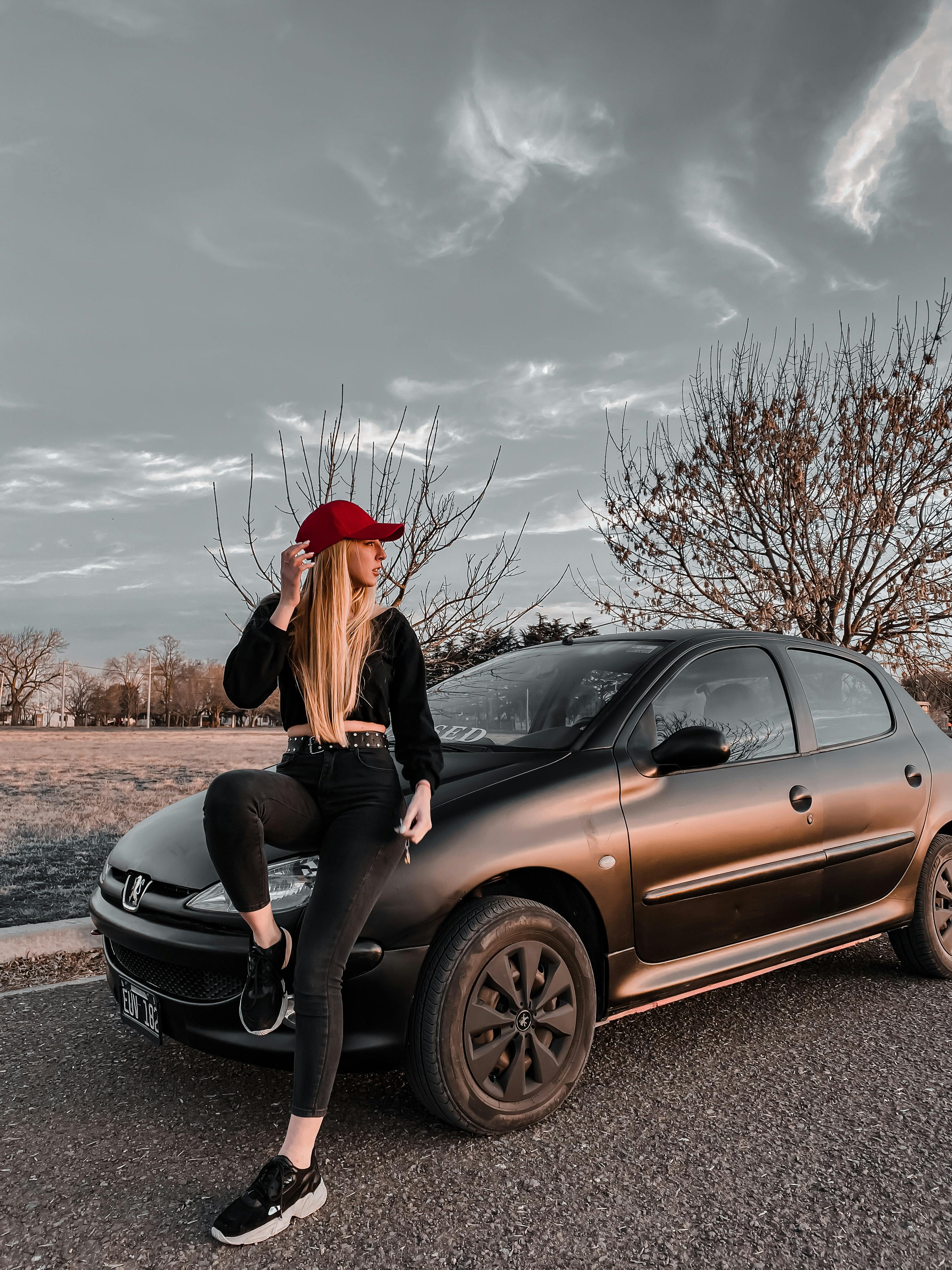 Woman in Red Cap Posing on Black Car · Free Stock Photo