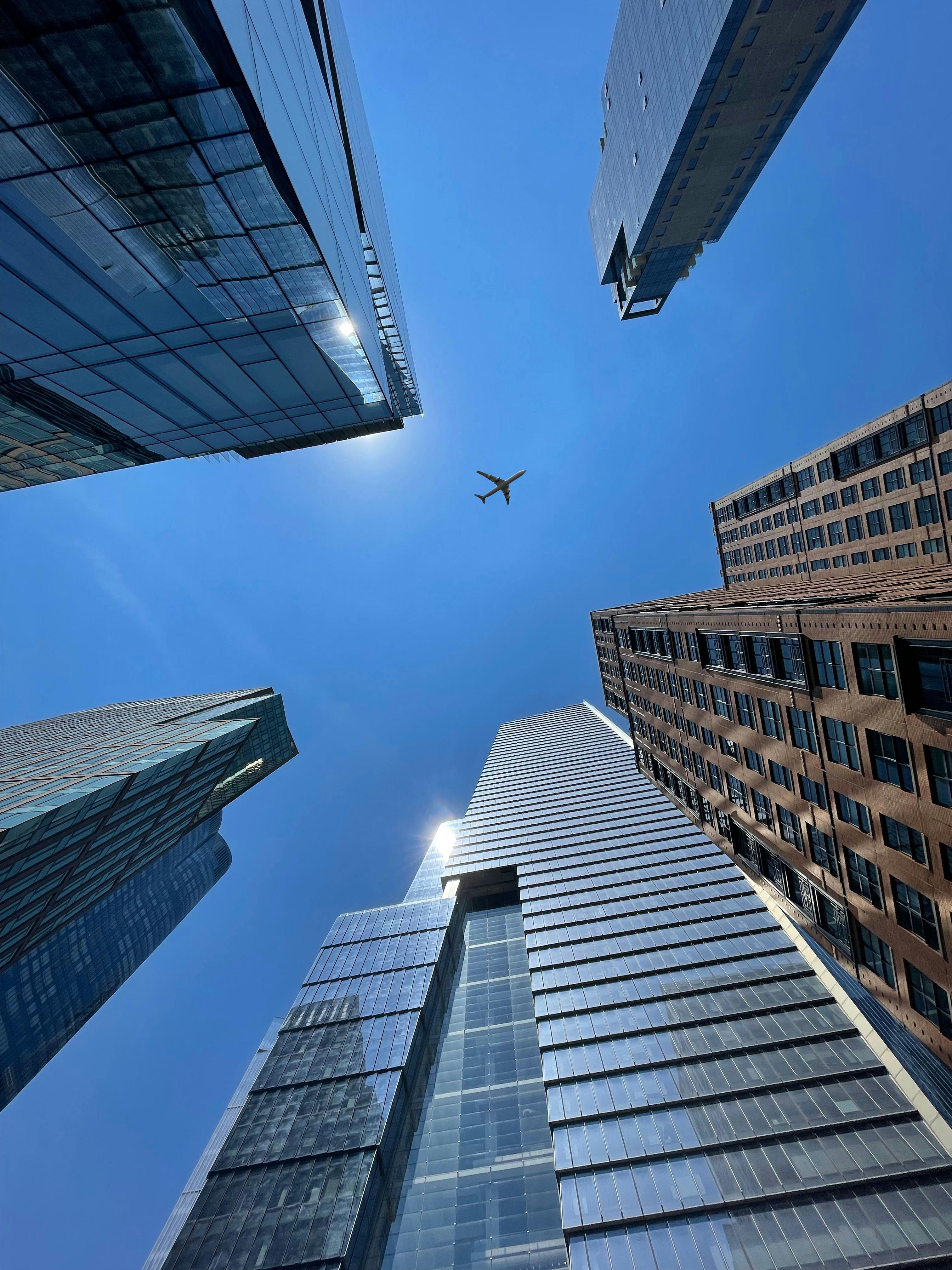 Low-Angle Photo of Airplane Flying over Building · Free Stock Photo