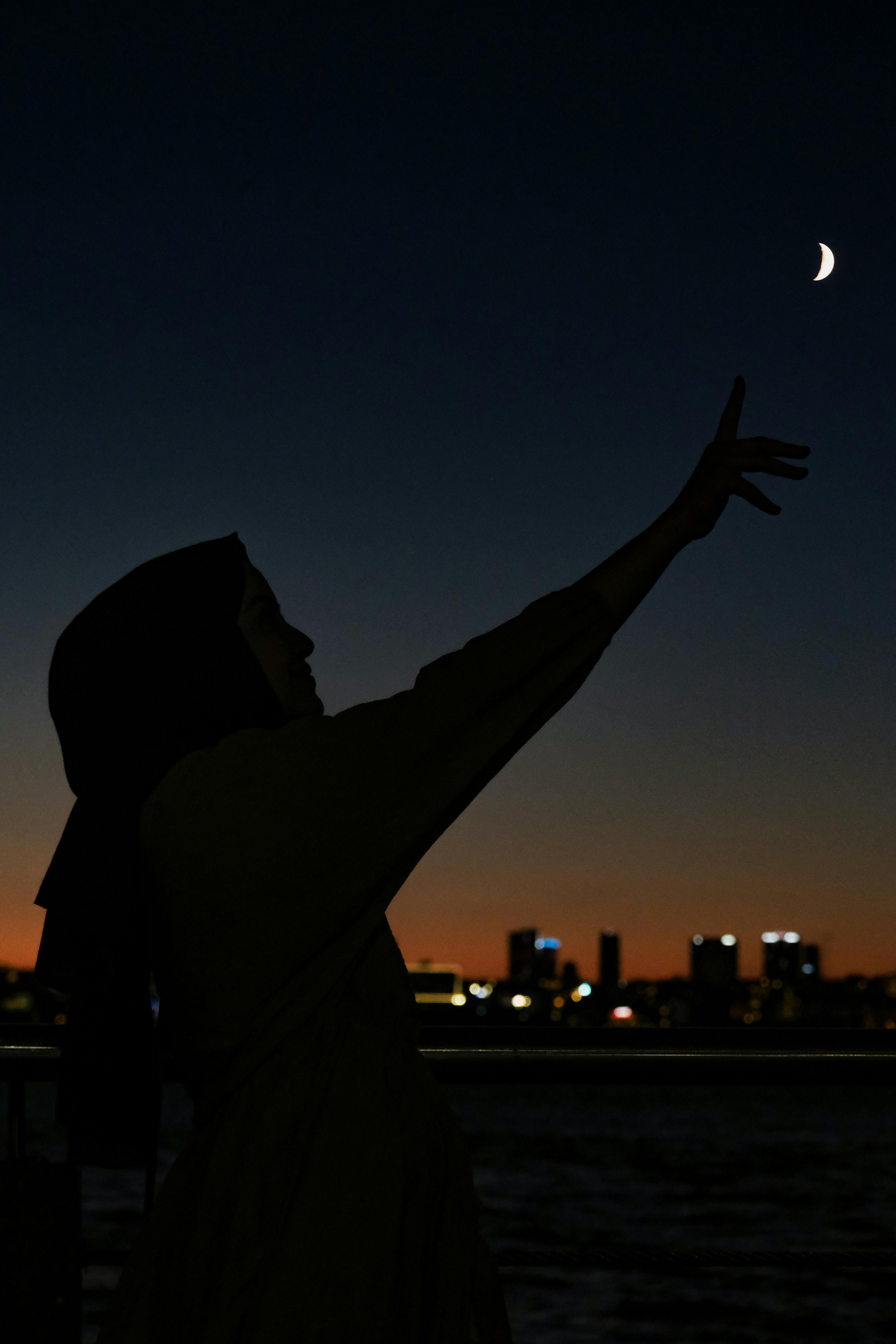 Silhouette of a Woman Reaching for the Moon · Free Stock Photo