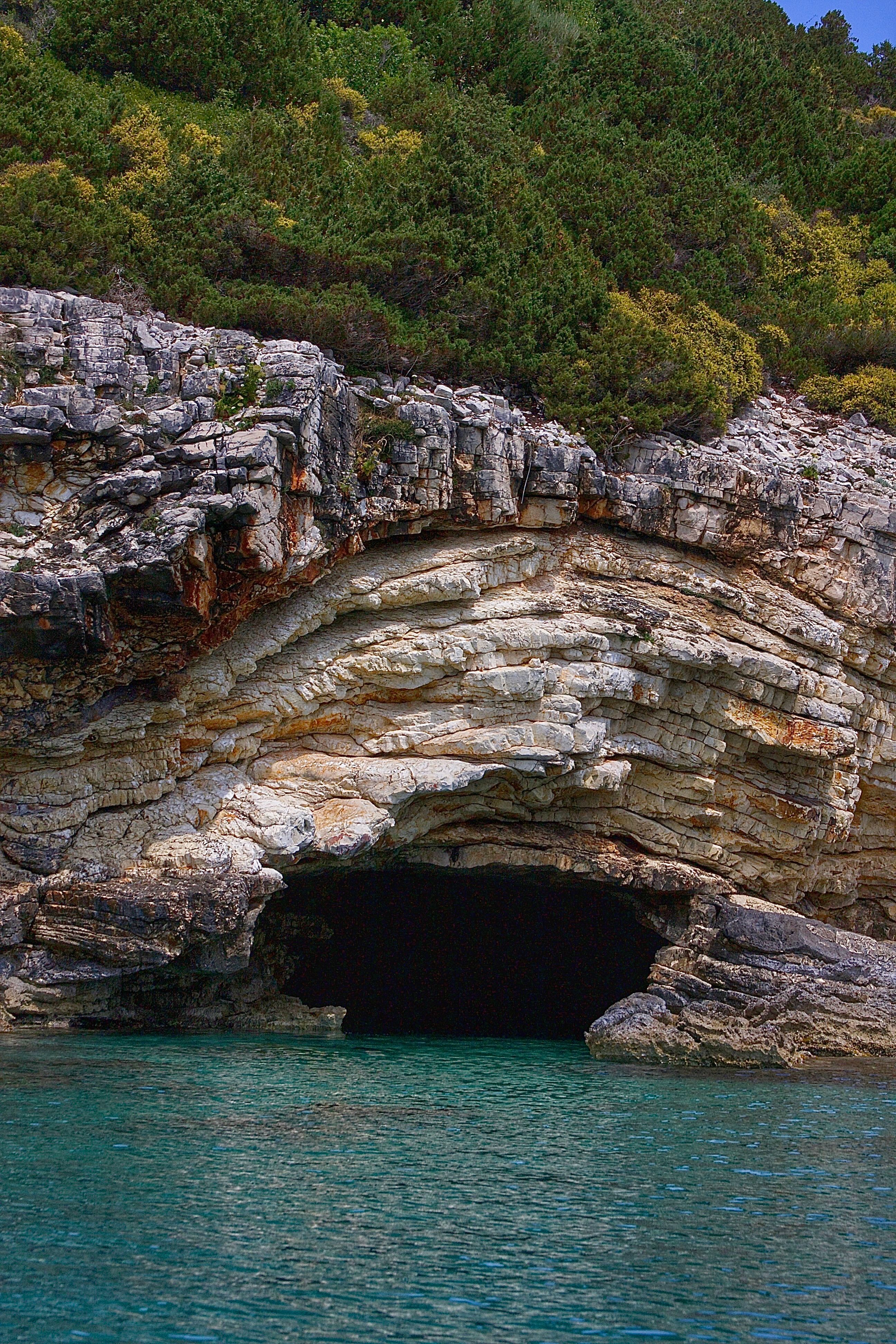 A Rock Formation with Green Trees Near the Body of Water · Free Stock Photo