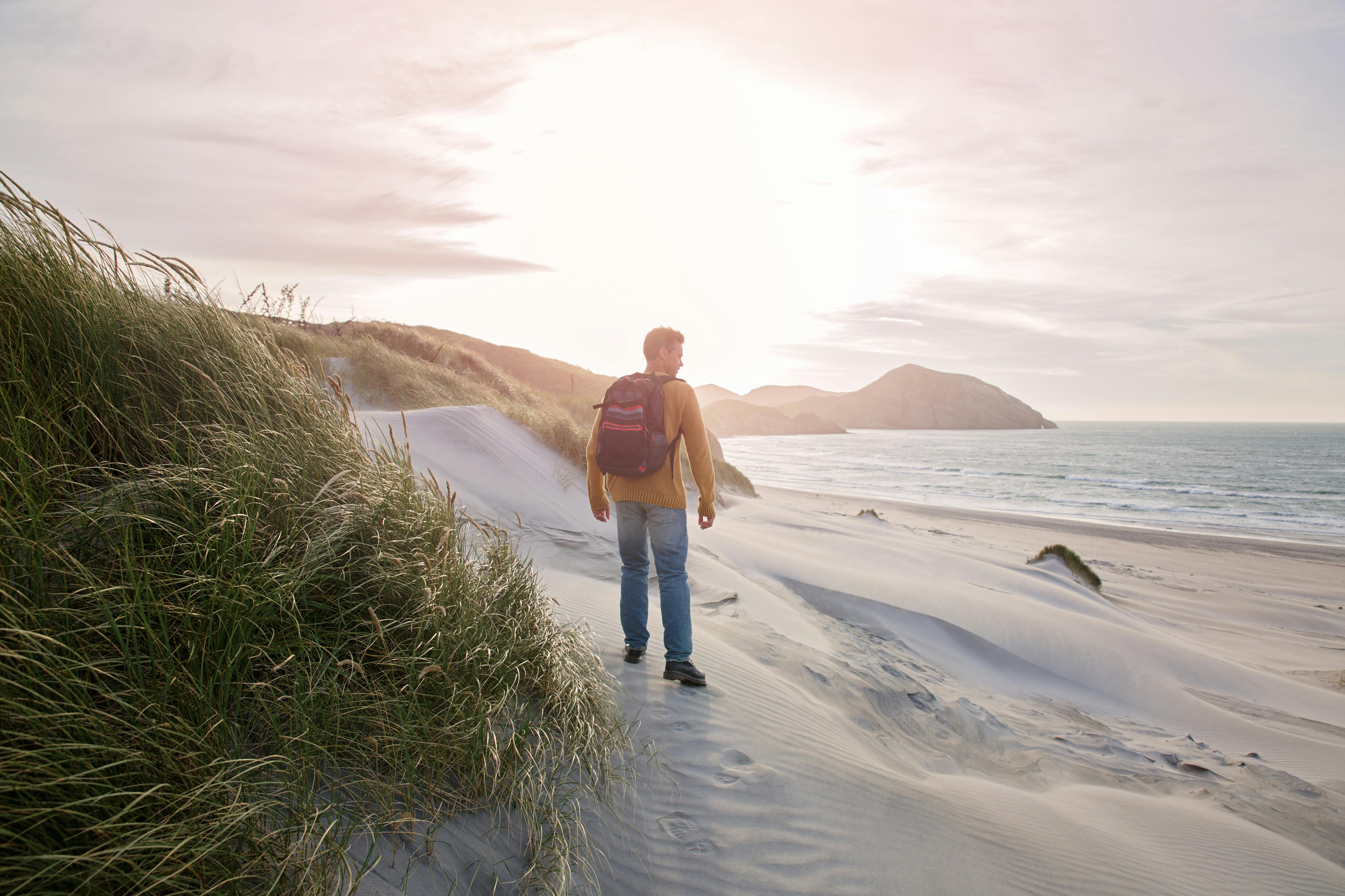 Man Carrying Black Backpack Standing on Seashore · Free Stock Photo