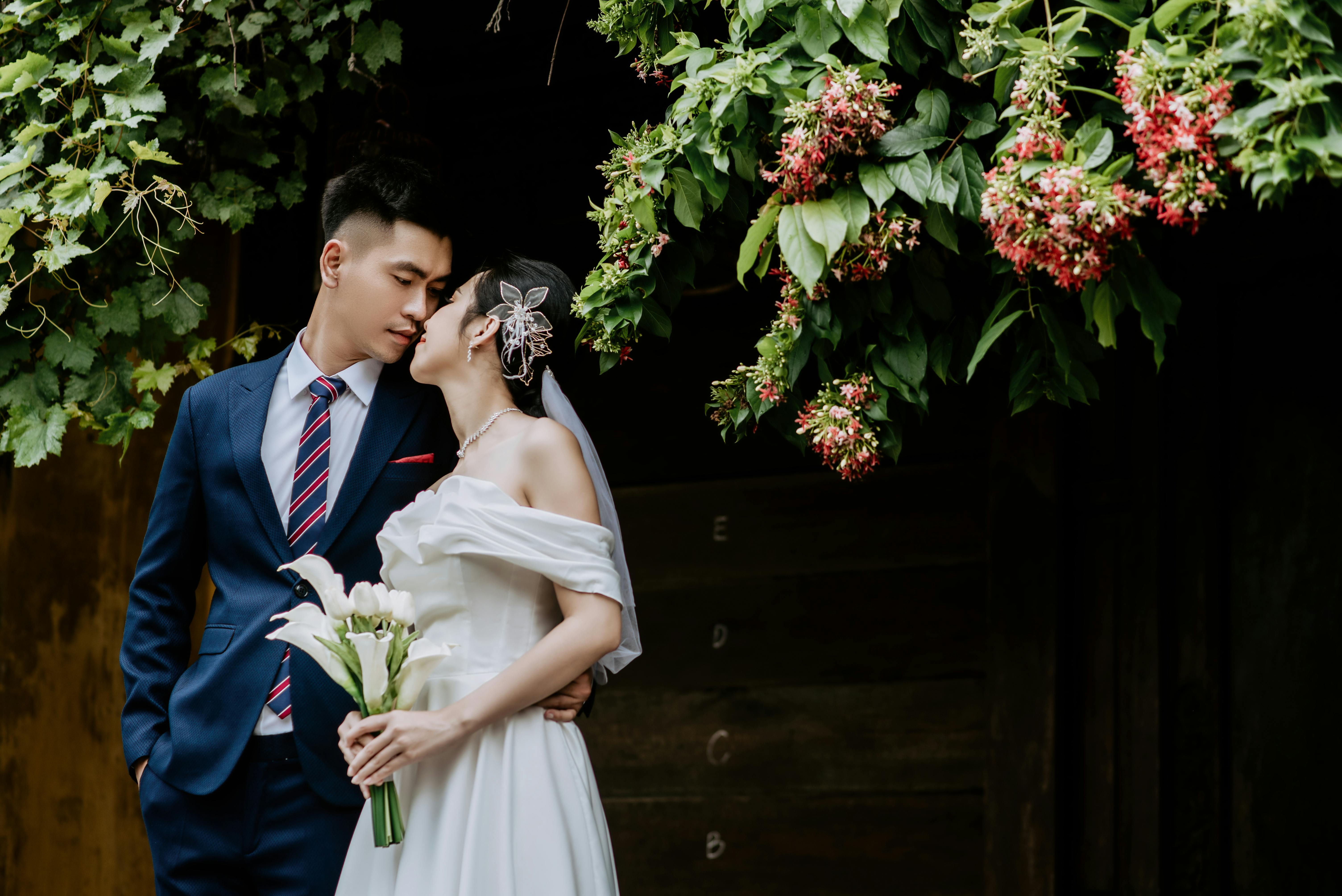 Bride and Groom Near Wooden Wall and Green Leaves · Free Stock Photo
