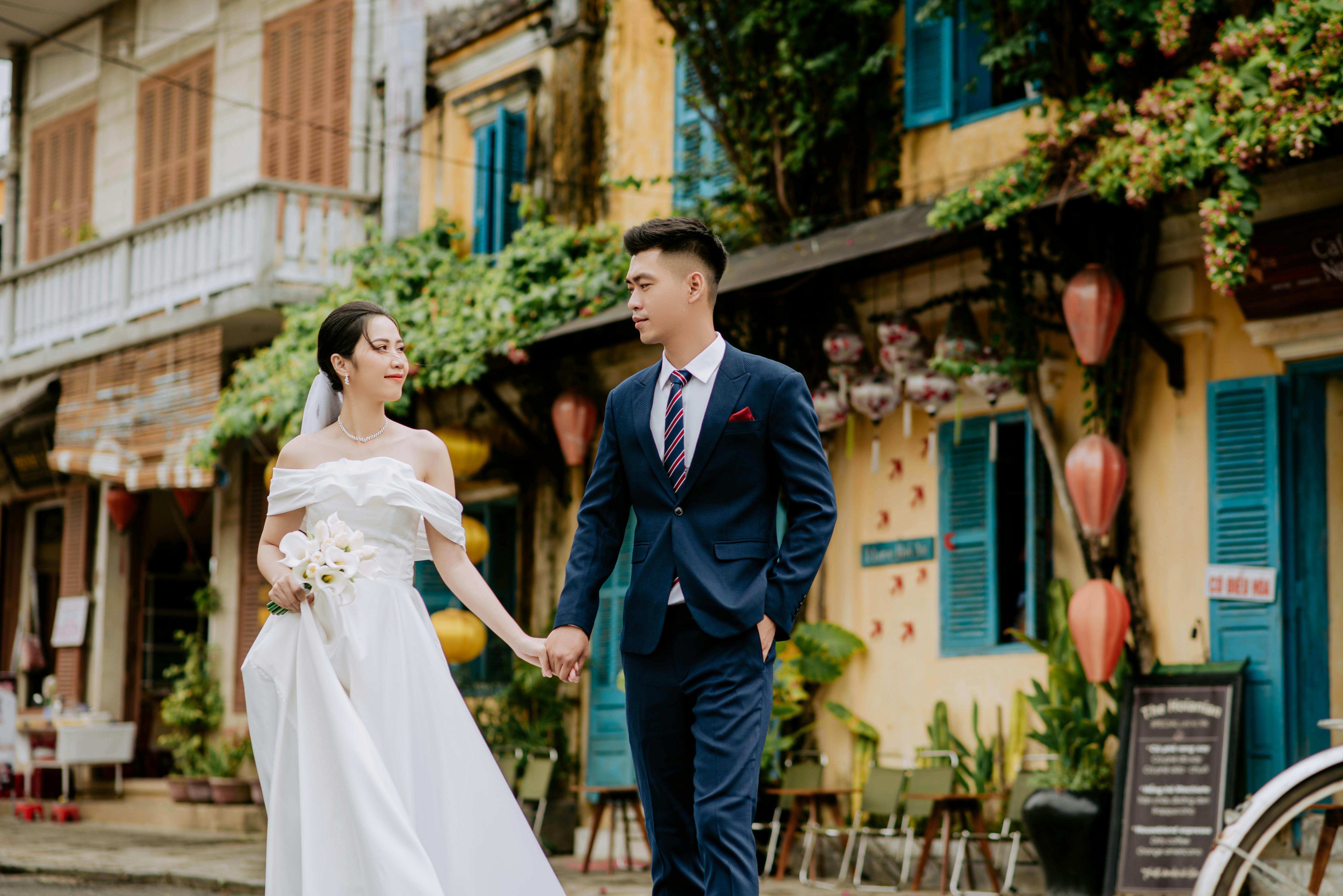 A Bride and a Groom walking while Holding Hands · Free Stock Photo
