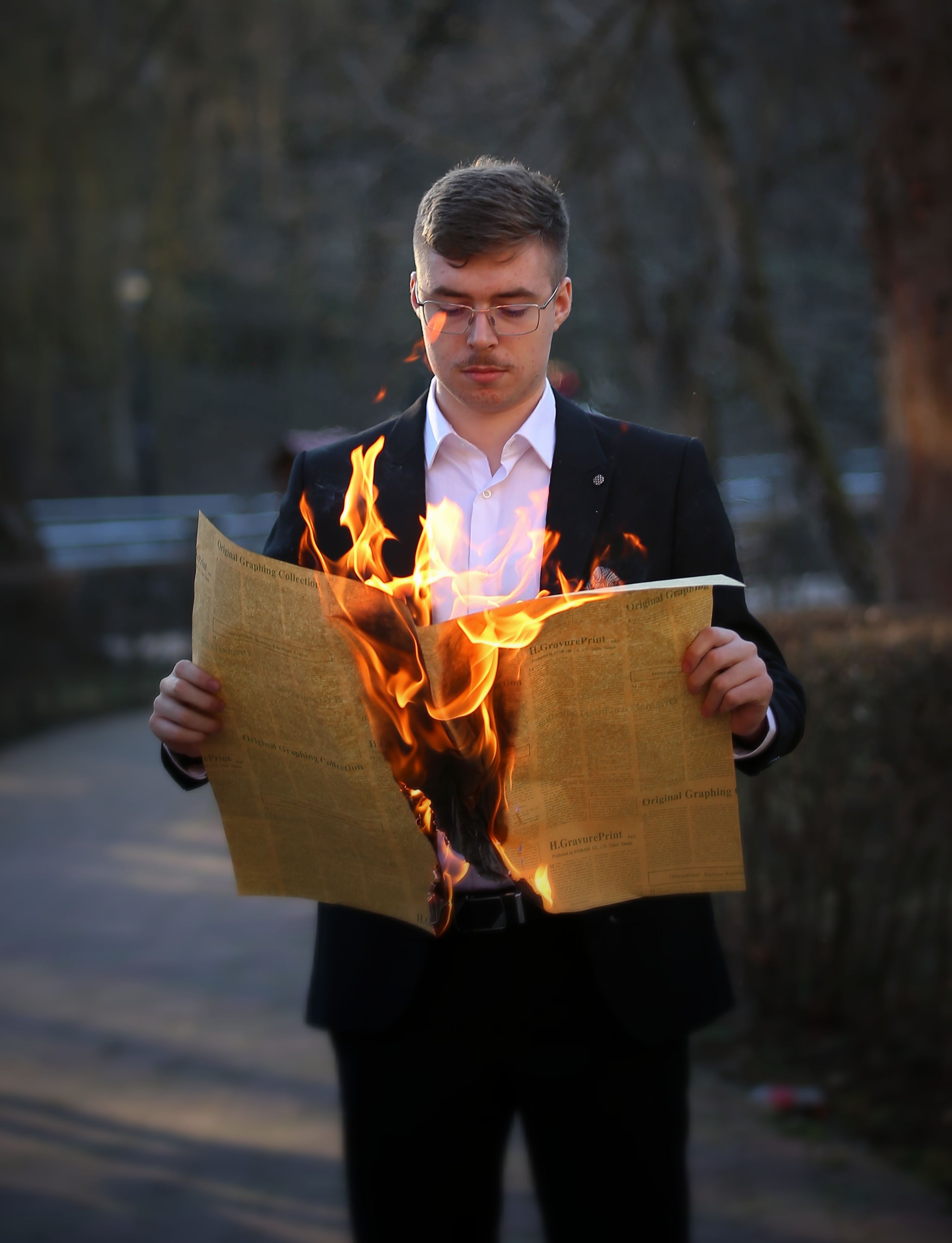 Man Sitting on Road and Holding Burning Newspaper · Free Stock Photo
