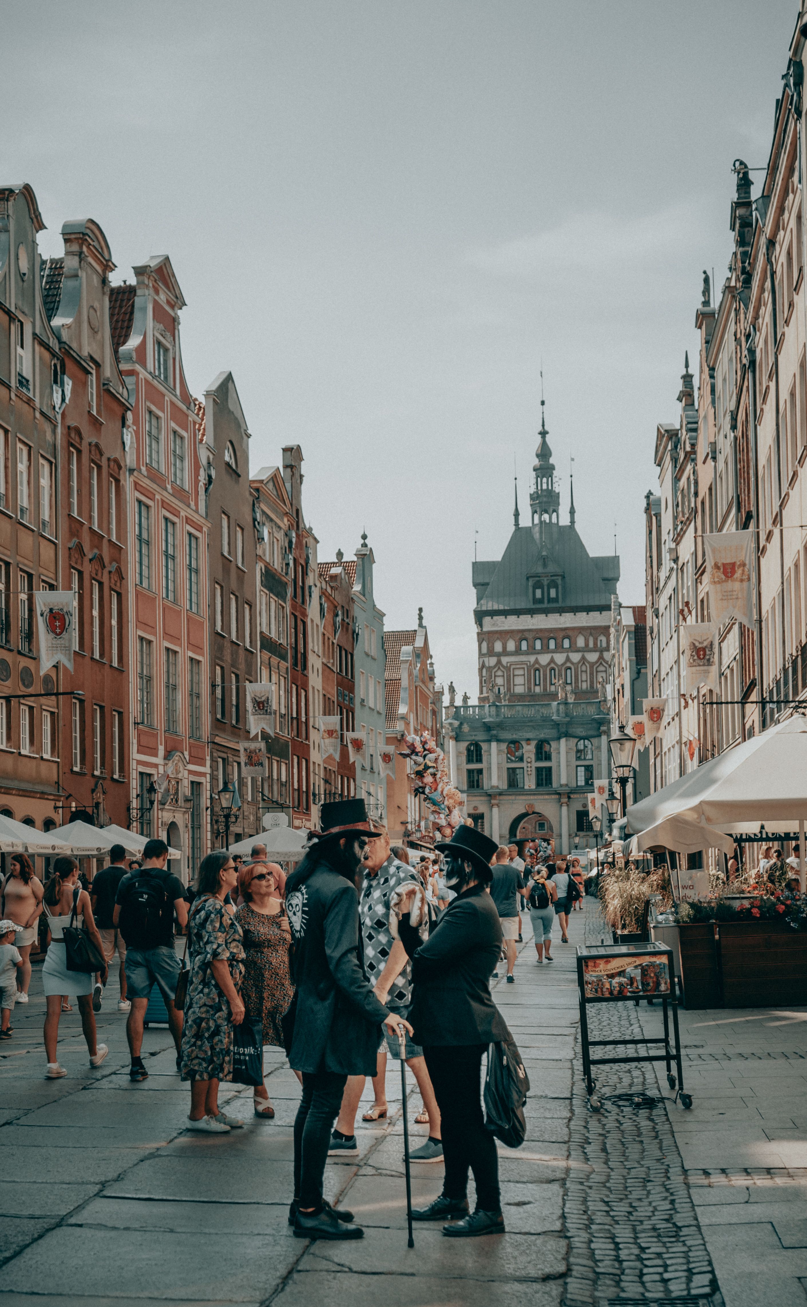 People Walking On City Street Between Concrete Buildings During