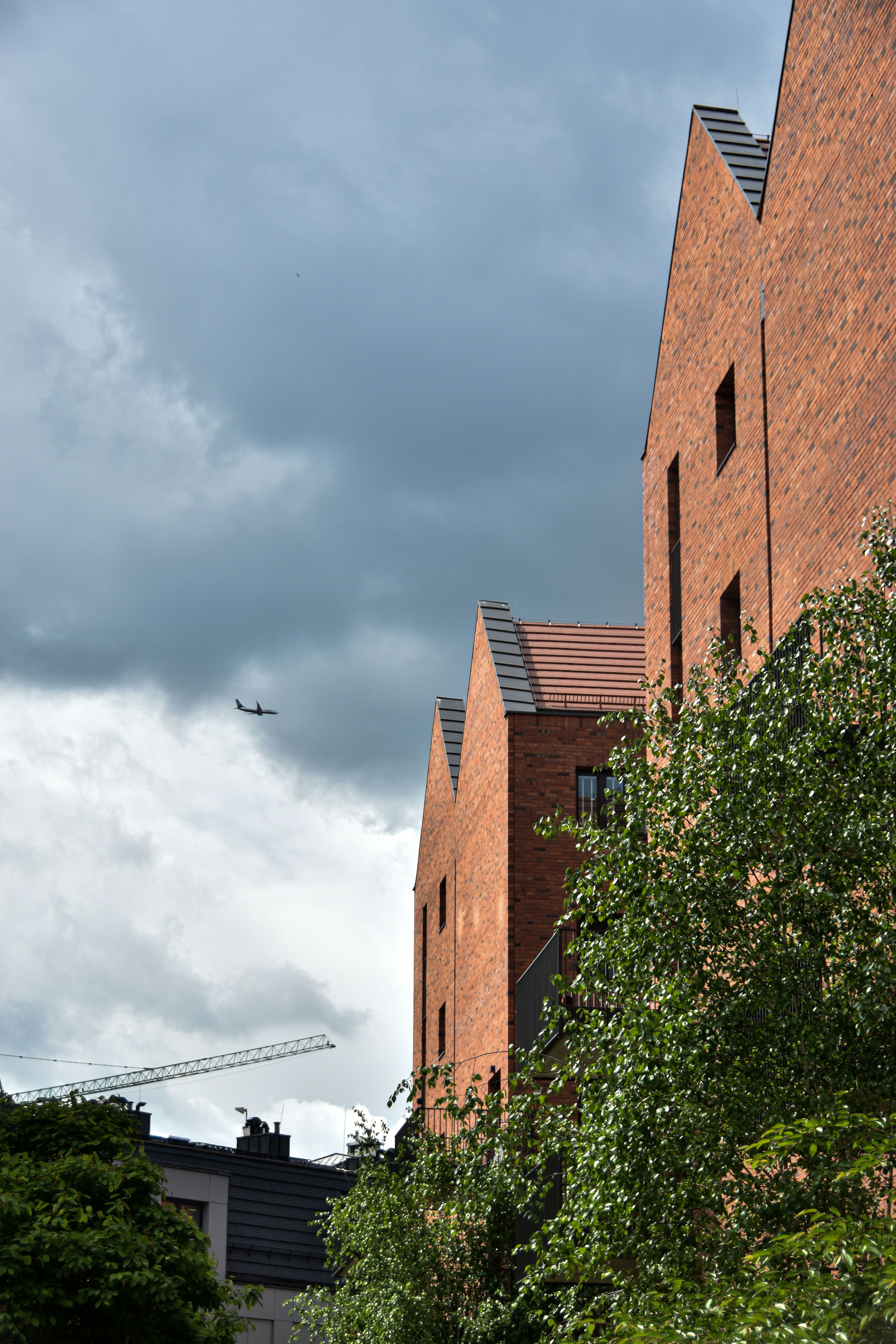 Airplane under Clouds on Sky over Town · Free Stock Photo
