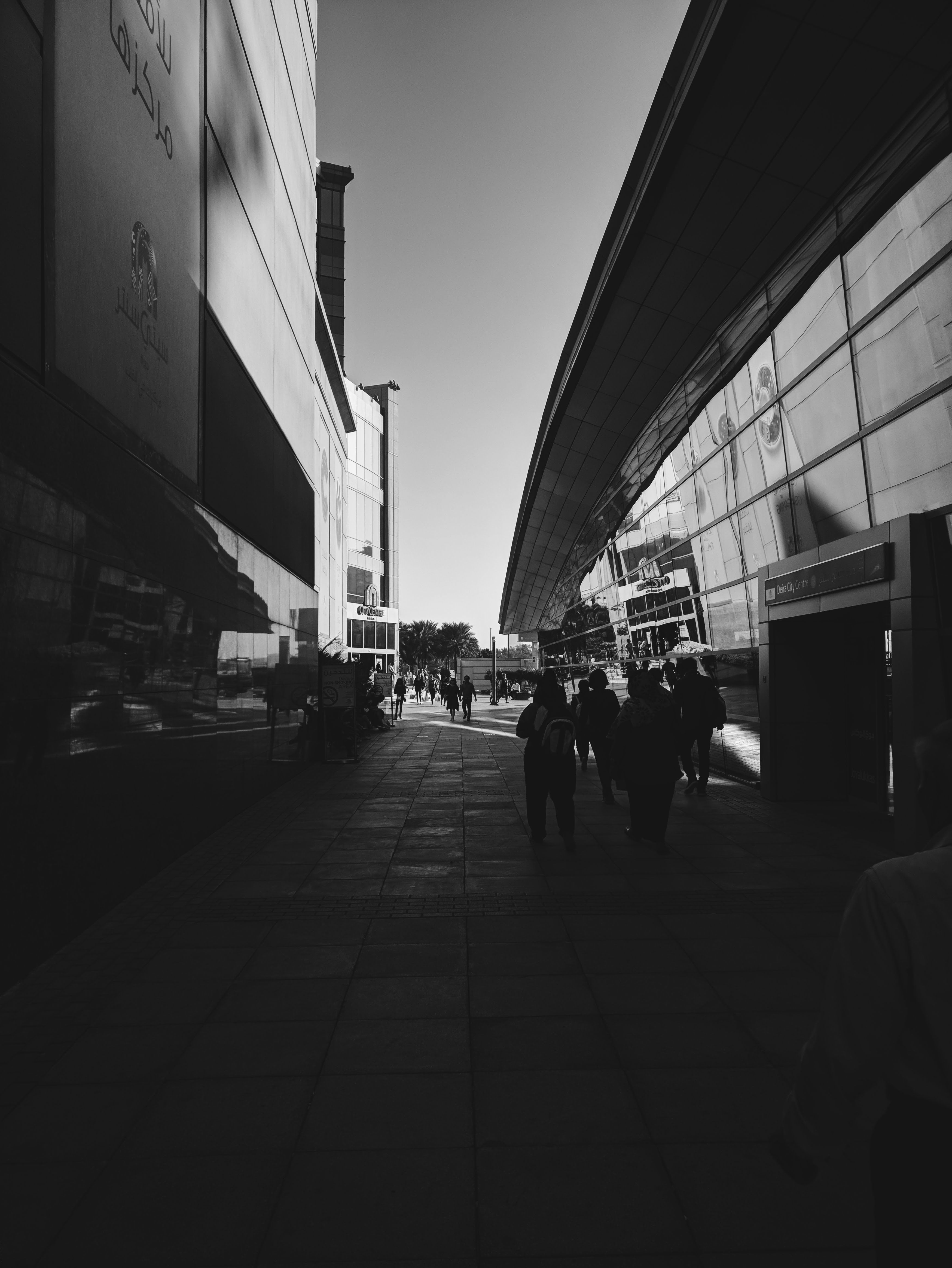 Grayscale Photo of People Walking Between the Buildings · Free Stock Photo
