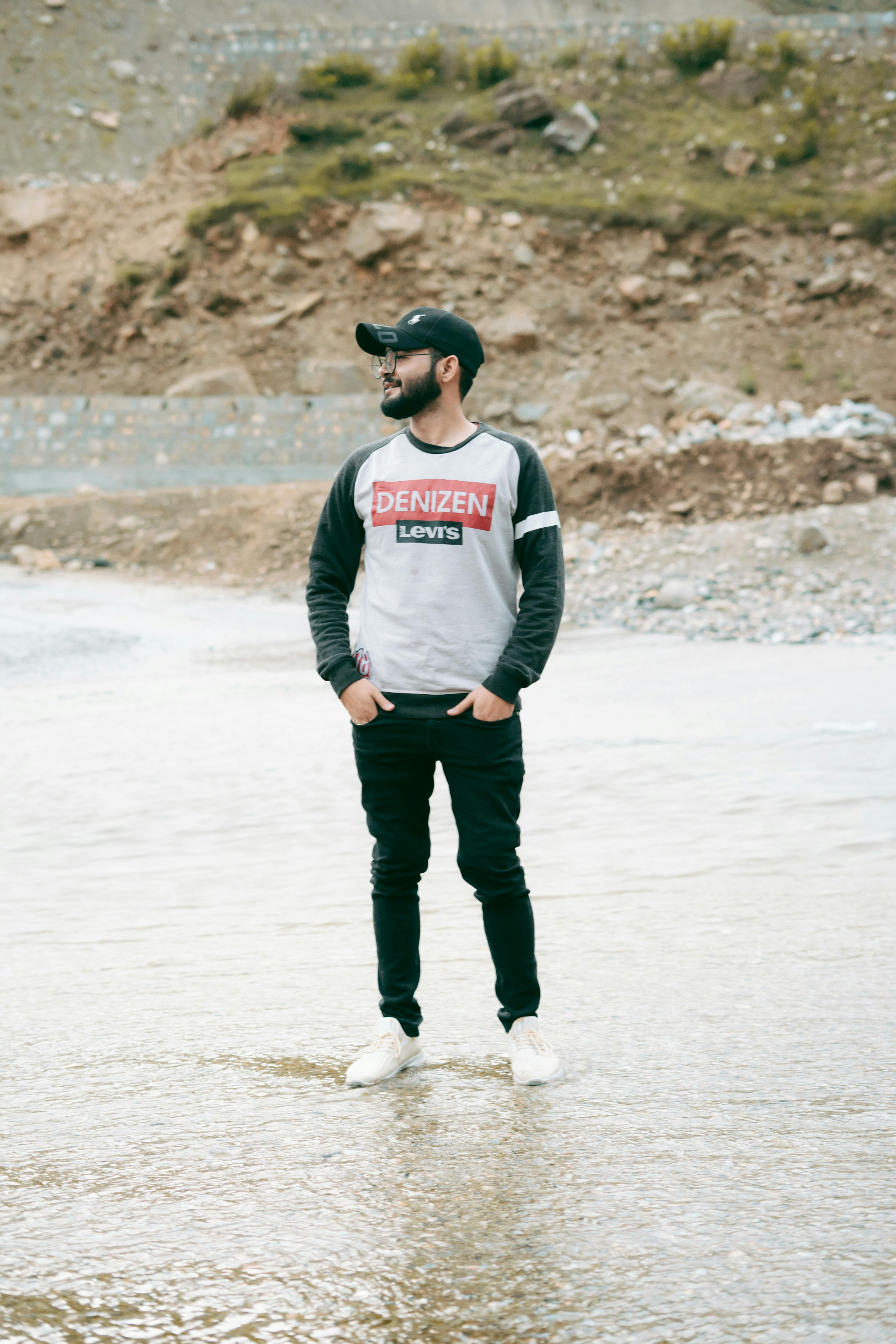 A Man with a Cap Standing on a Beach · Free Stock Photo