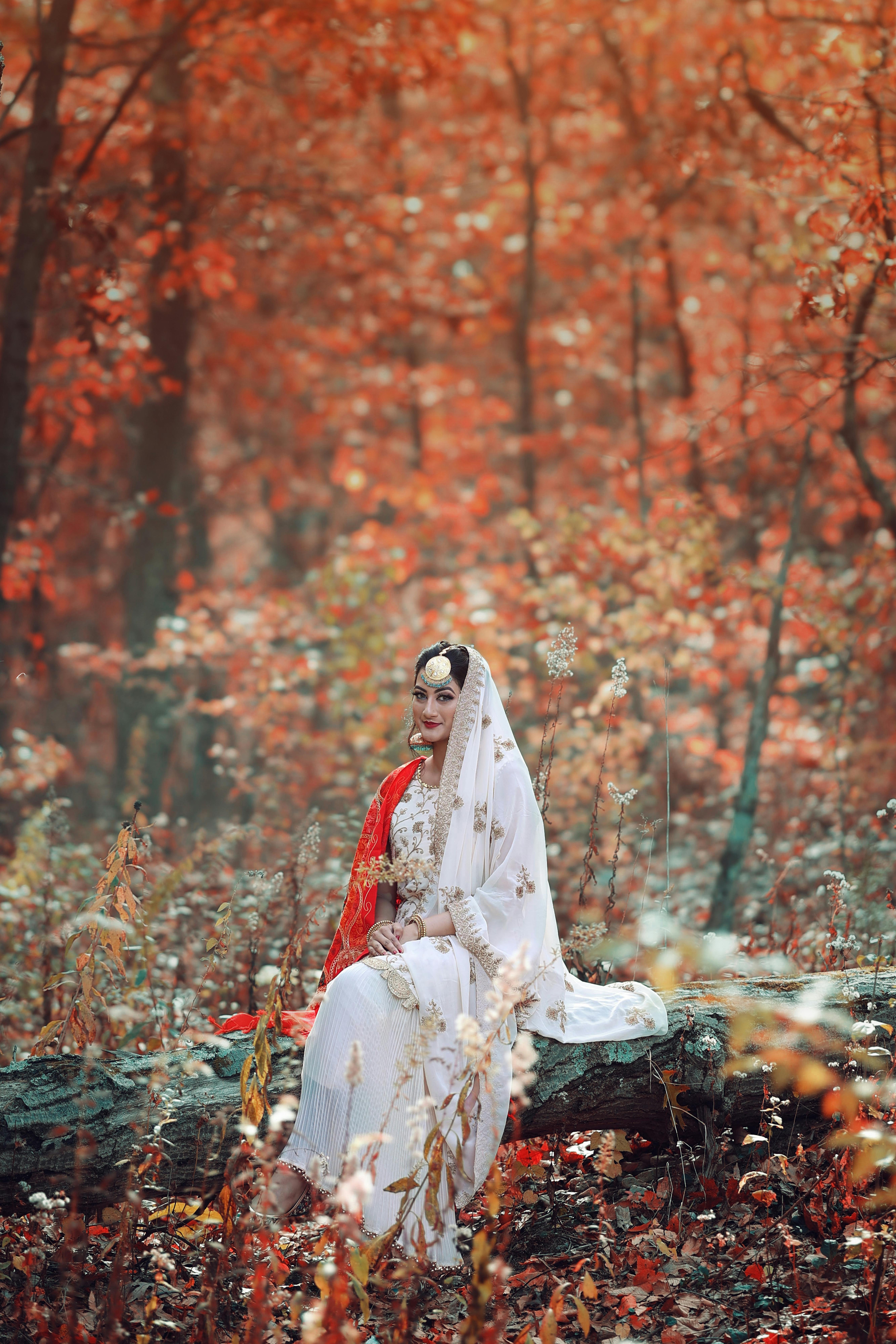Woman in Traditional Clothes Sitting on Ground in Forest · Free Stock Photo