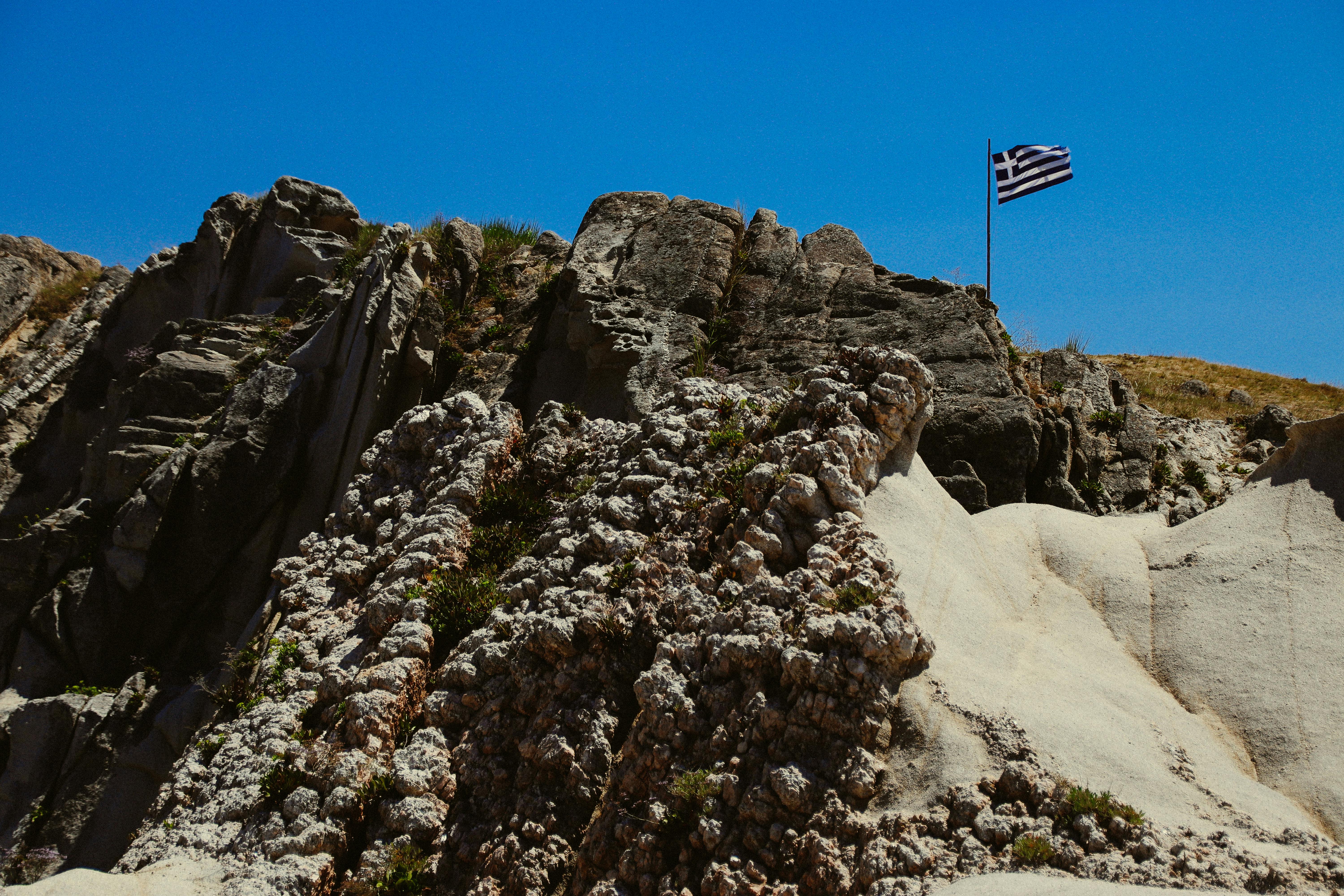 Flag of Greece over Rocks on Hill · Free Stock Photo