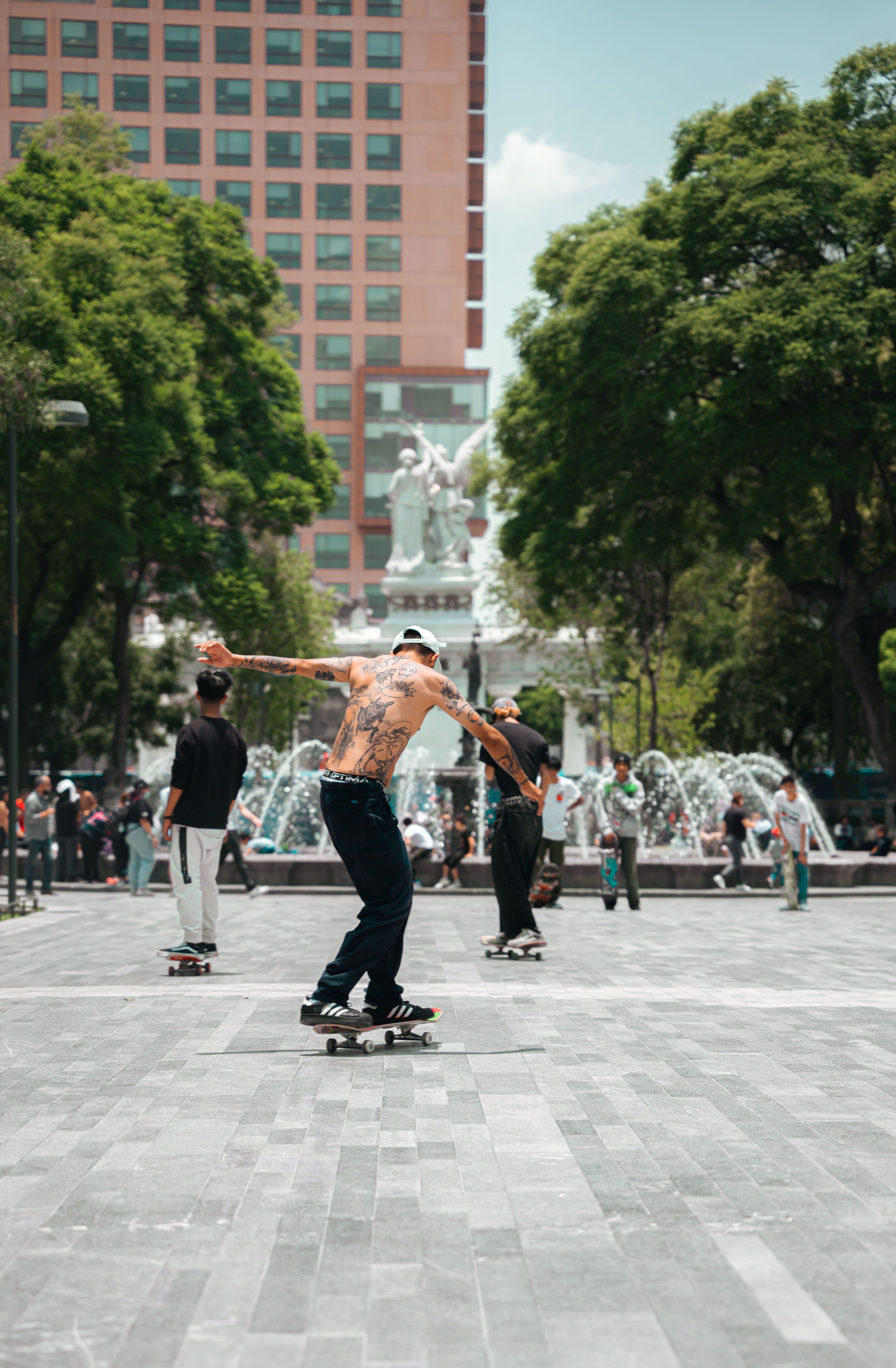 A Shirtless Tattooed Man Skateboarding at a Park · Free Stock Photo