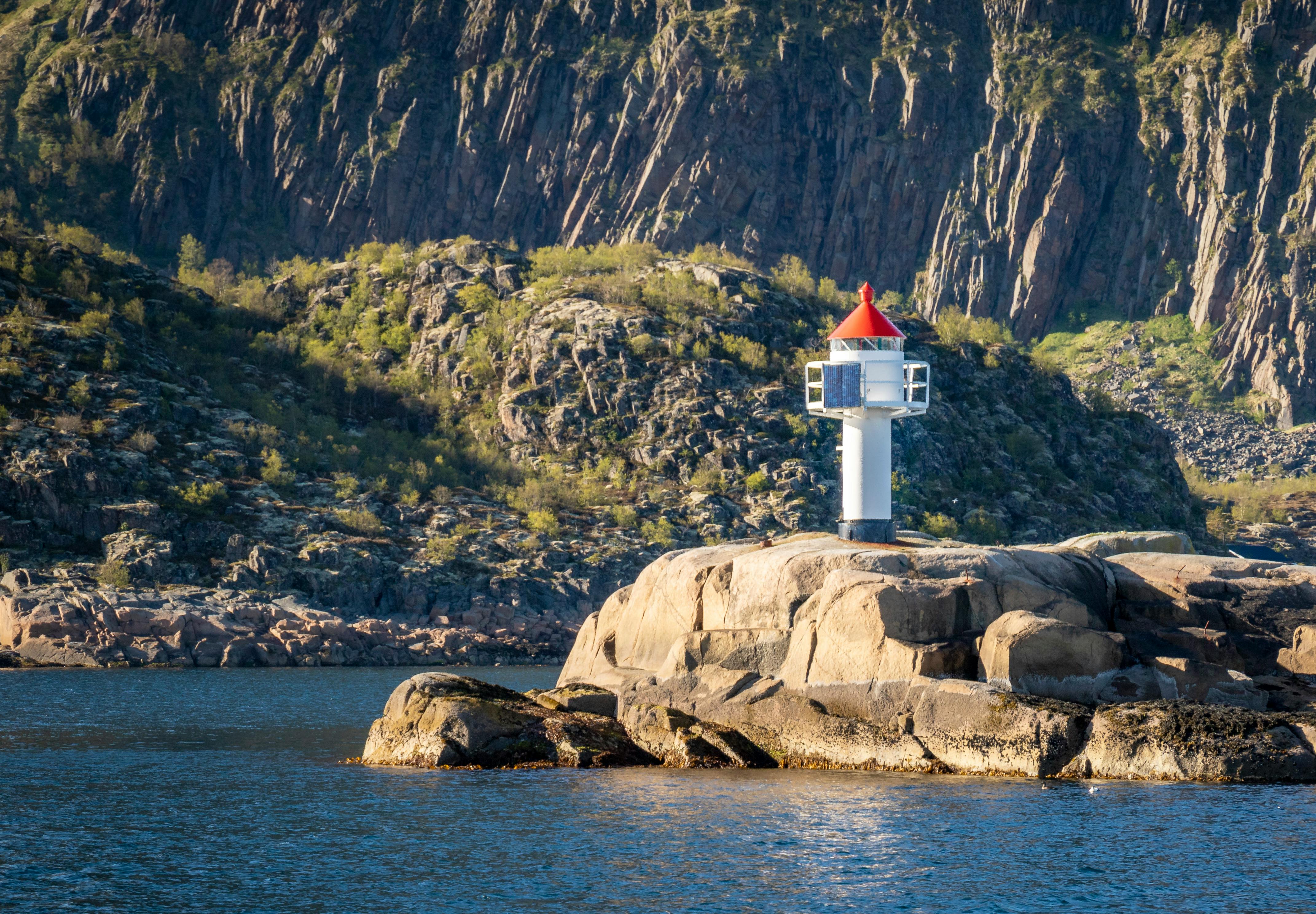 White and Red Lighthouse on Rocky Shore · Free Stock Photo