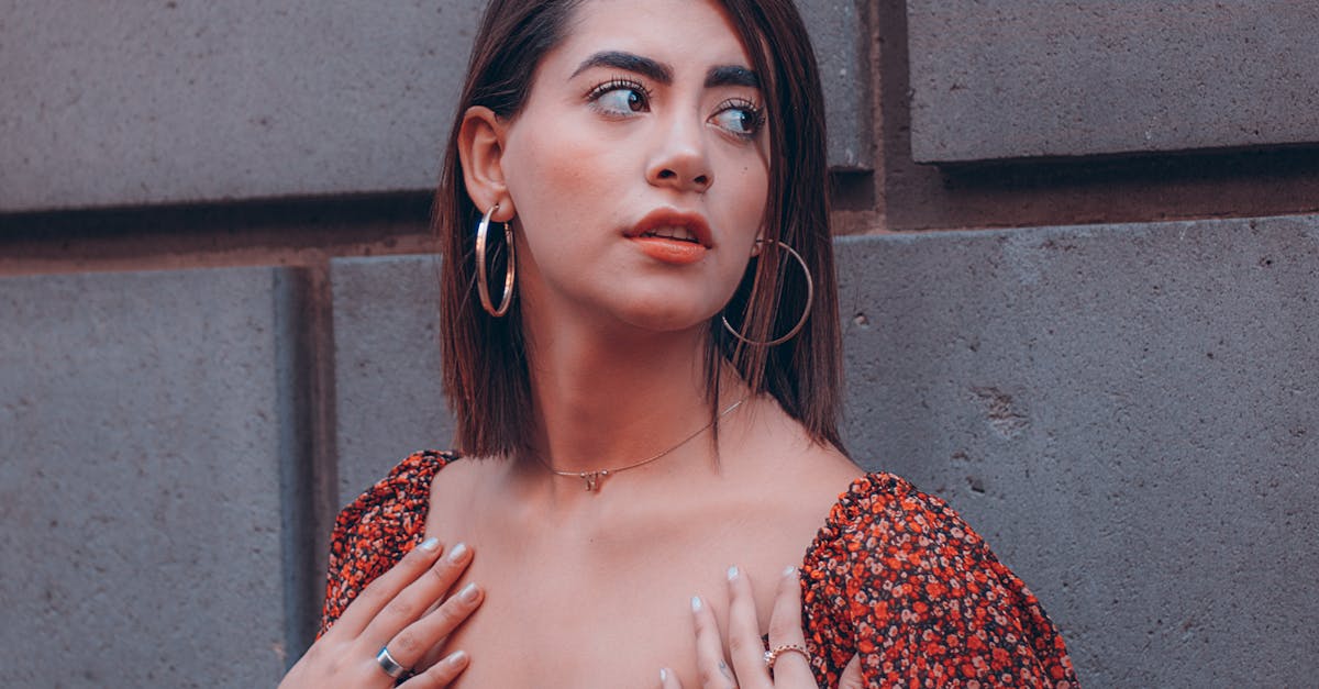 Portrait Of A Woman In Red Floral Dress Standing Near A Concrete Wall