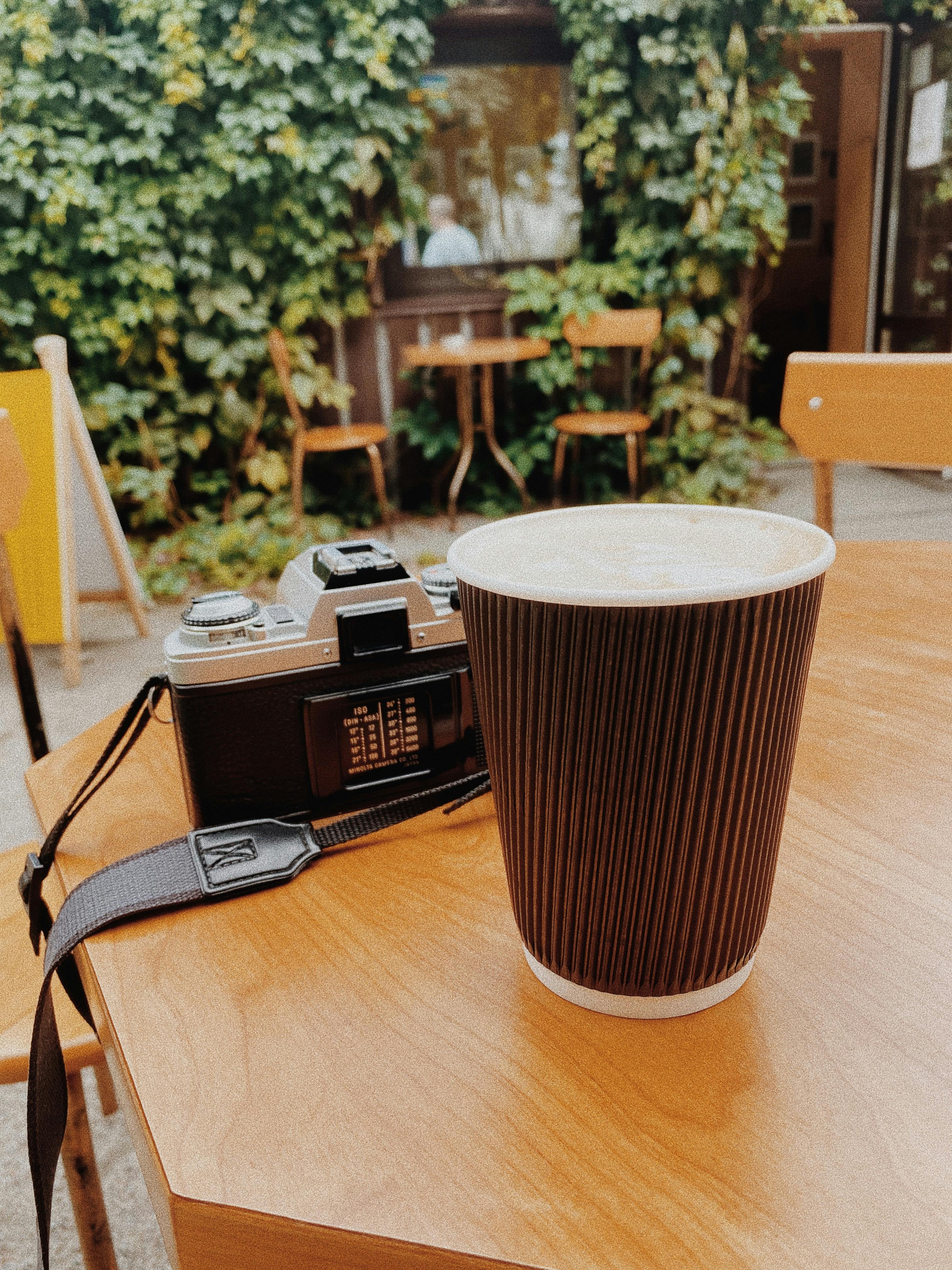 Brown and White Coffee Cup Beside Camera on Brown Wooden Table · Free ...