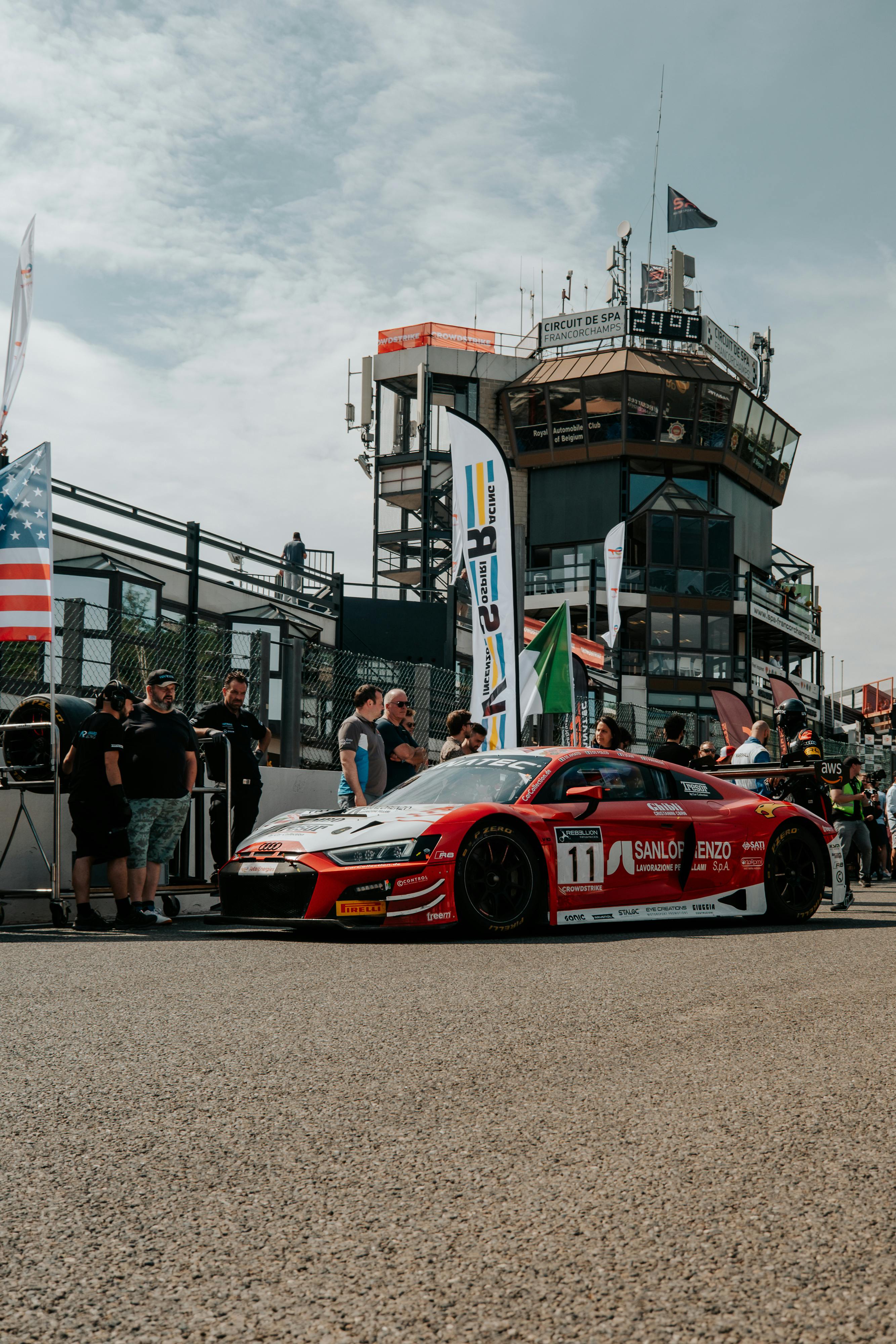 People Near a Red Racing Car on an Asphalt Road · Free Stock Photo