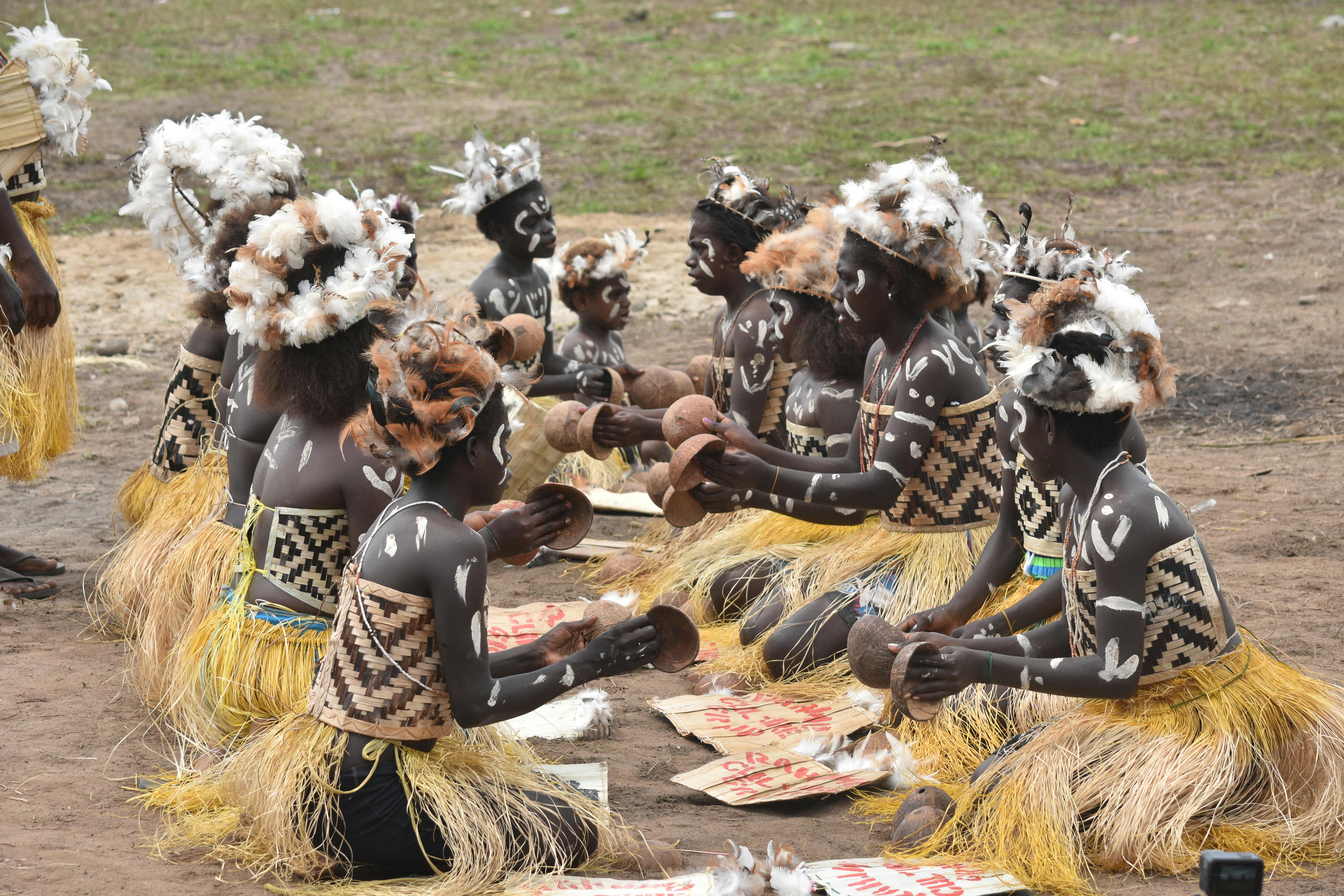 People Wearing Tribal Clothing and Feather Plumes Sitting on a Ground ...