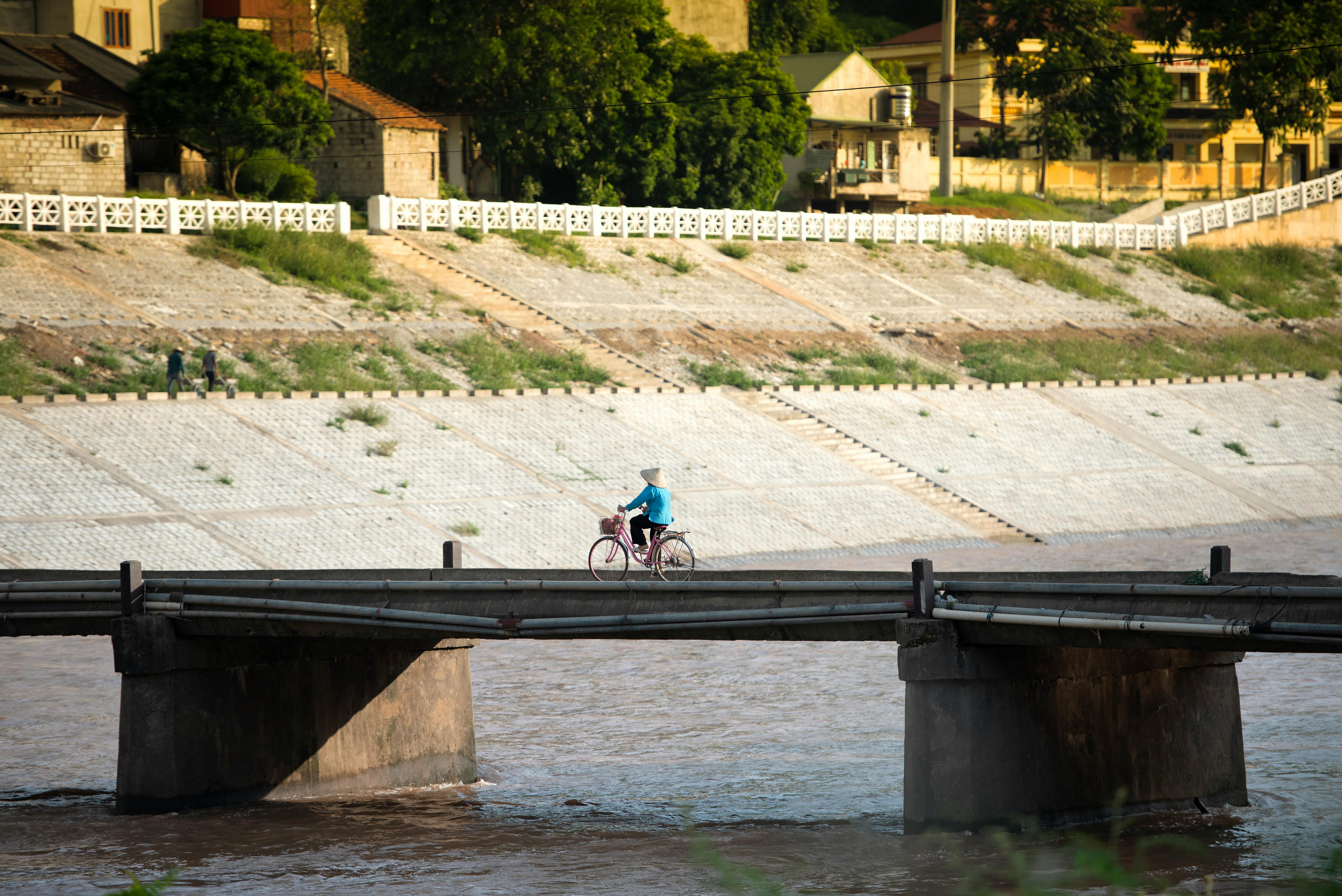 A Person Riding a Bike on the Concrete Bridge · Free Stock Photo