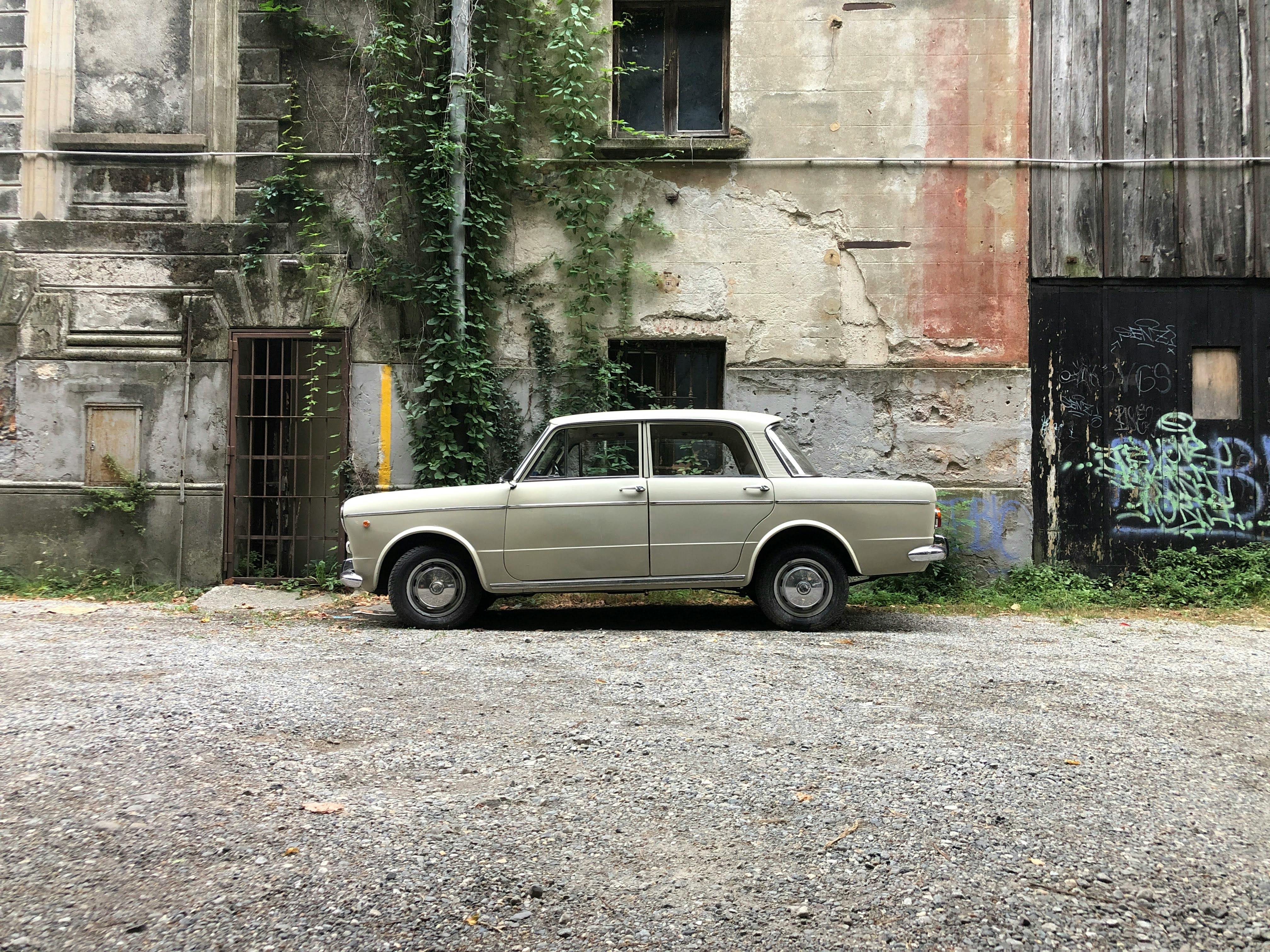 Vintage Car Parked Beside an Old Concrete Building · Free Stock Photo