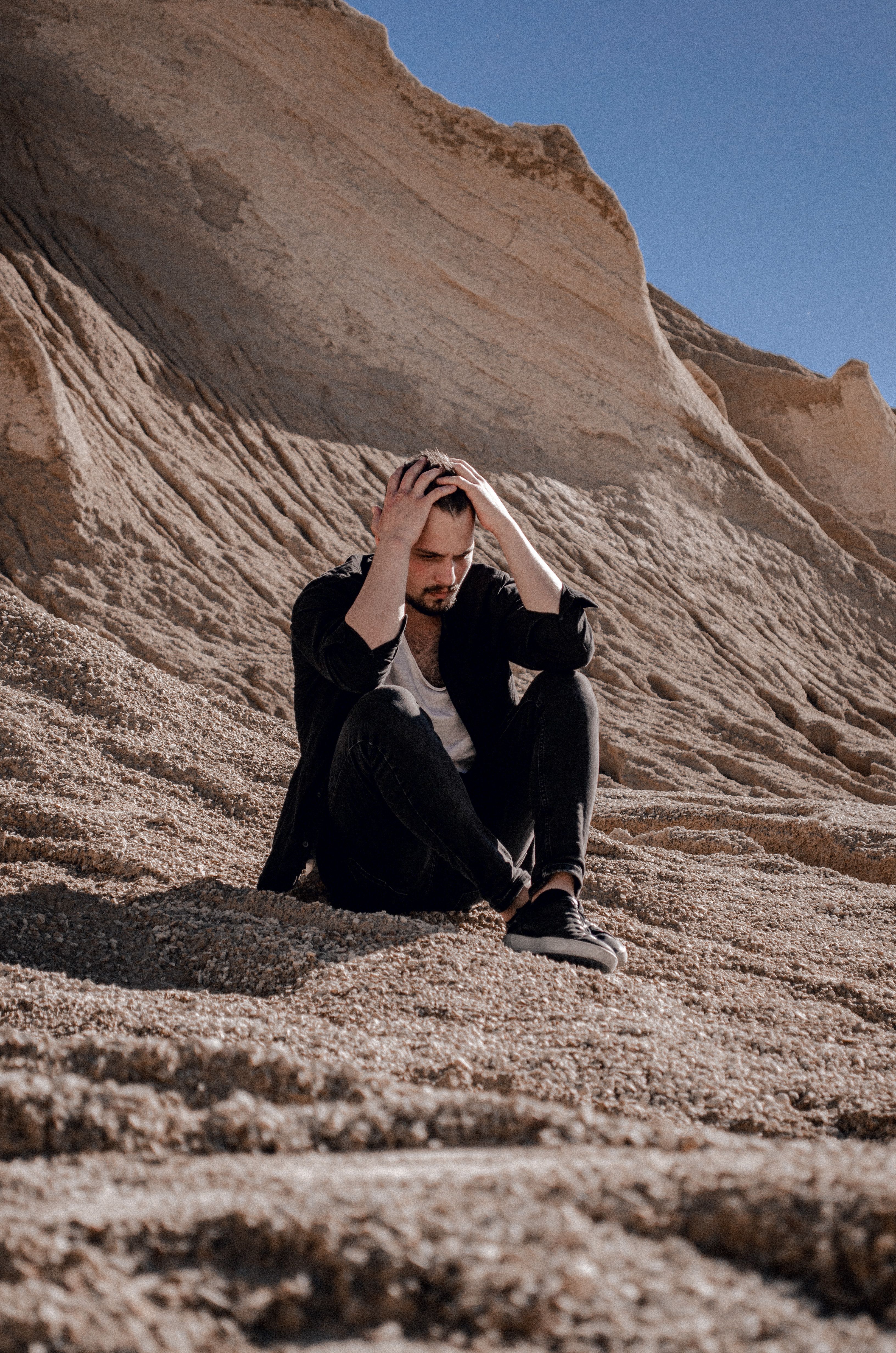 Man Sitting on Beach near Cliff · Free Stock Photo