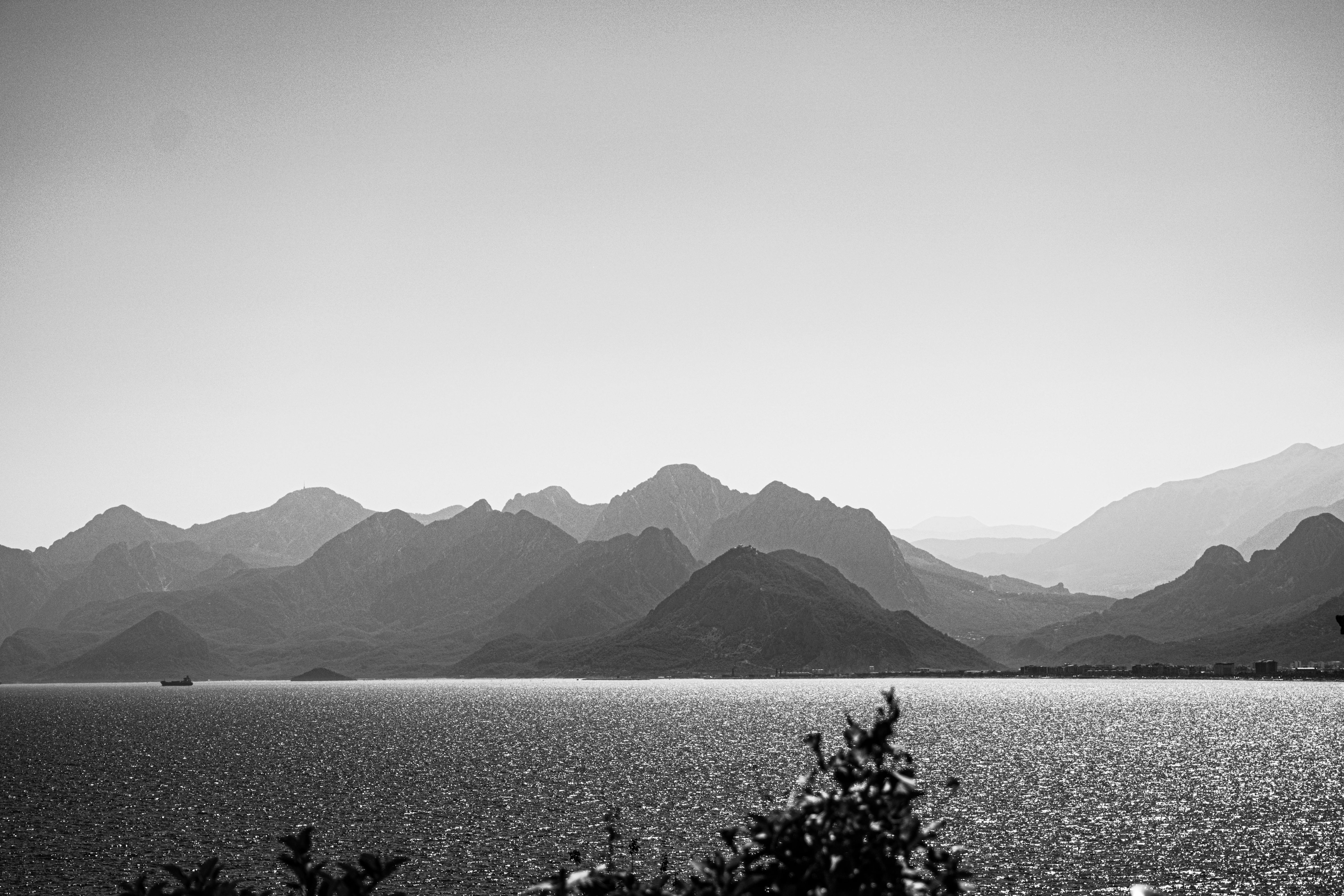 A Grayscale Photo of a Body of Water Near Mountains · Free Stock Photo