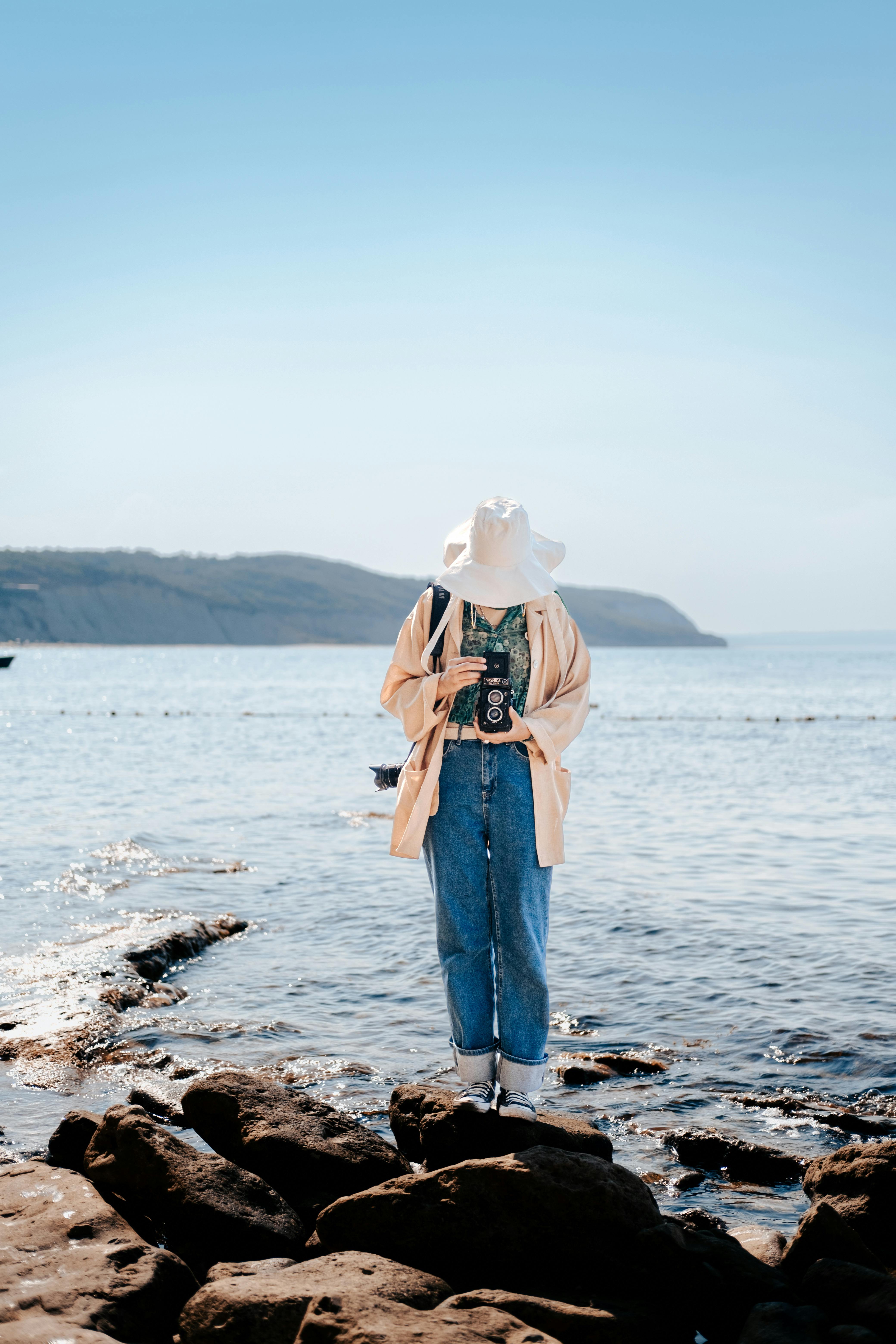 Woman in Hat on Rock near Water · Free Stock Photo