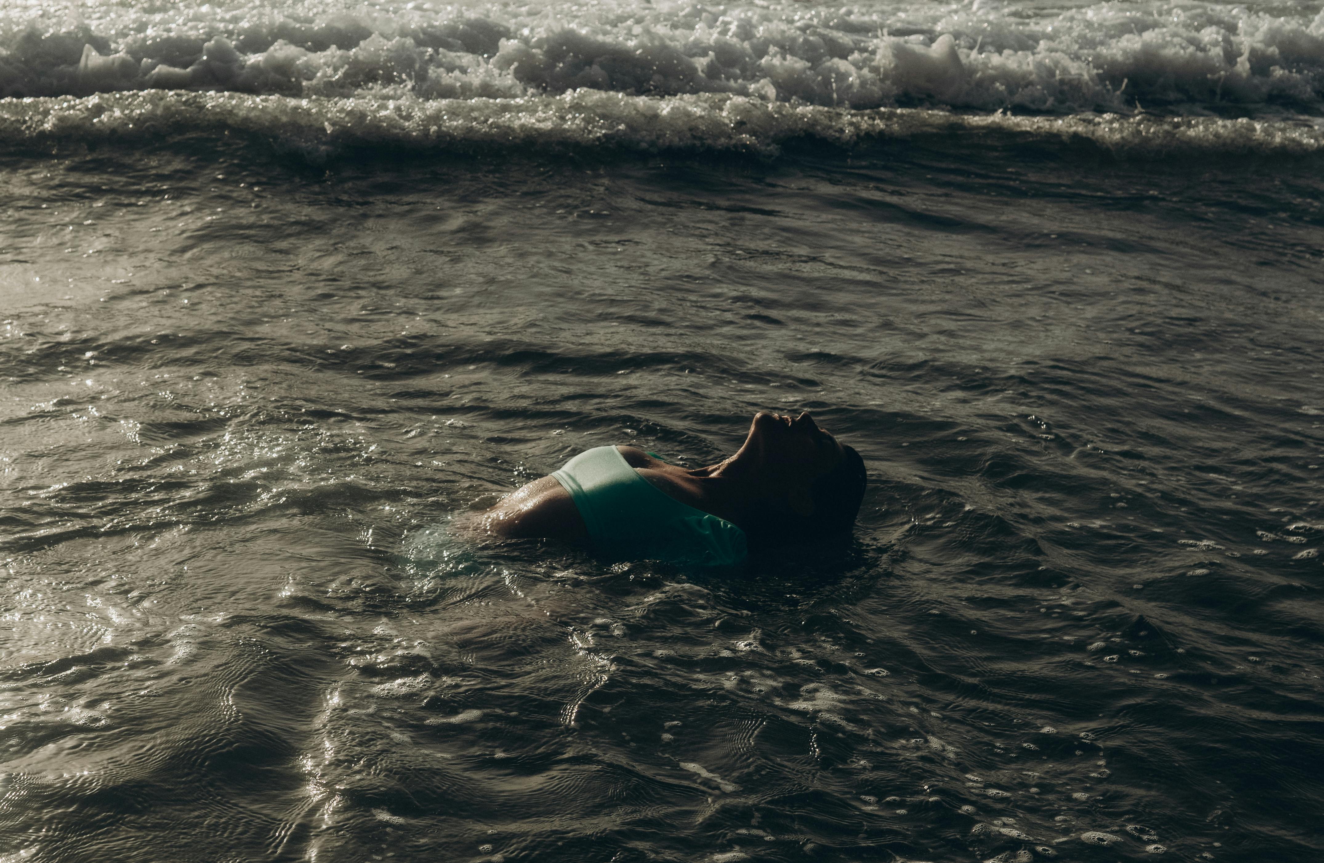 A Woman Wearing a Green Swim Suit Lying Down on Water · Free Stock Photo