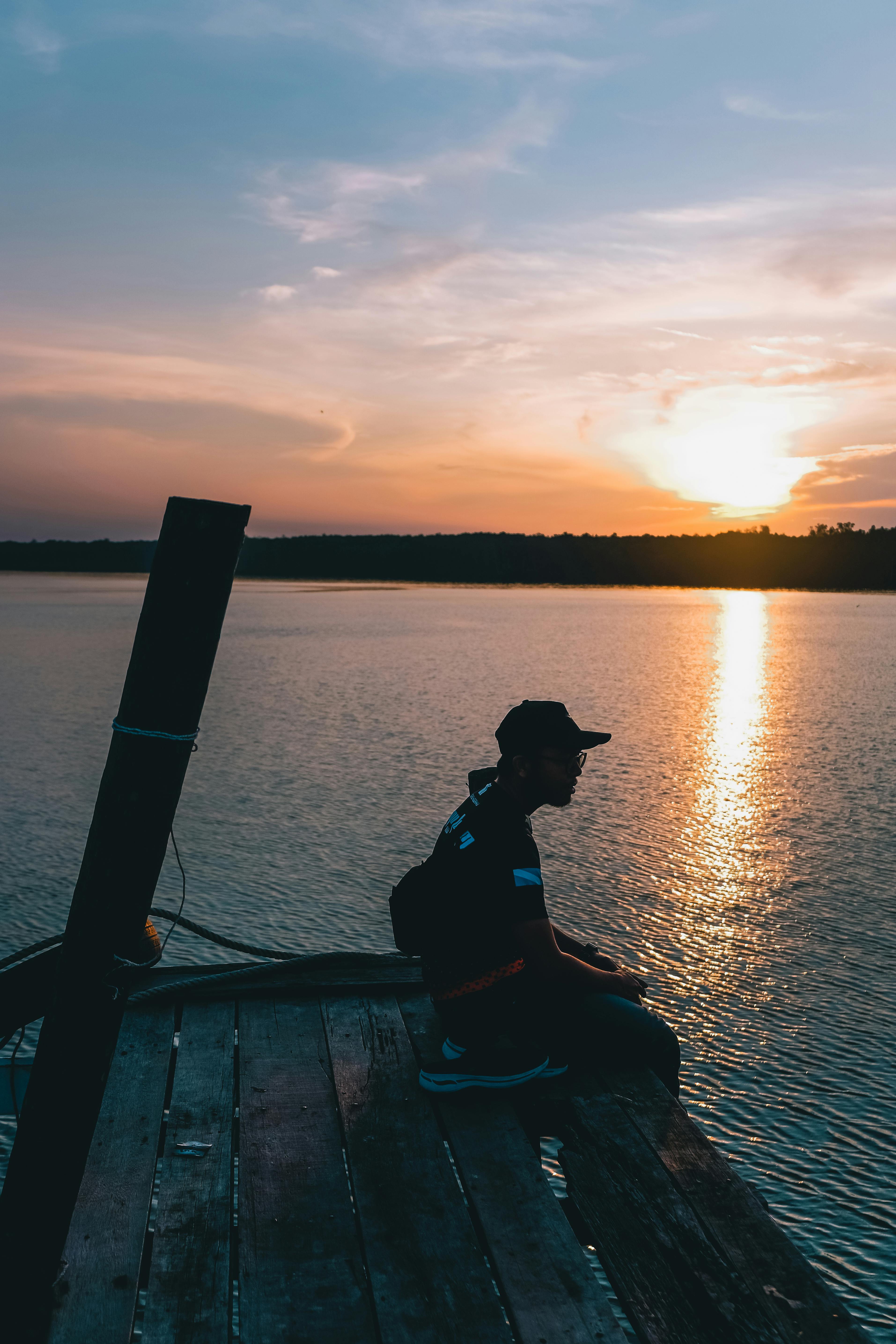 Man Sitting on Wooden Dock · Free Stock Photo