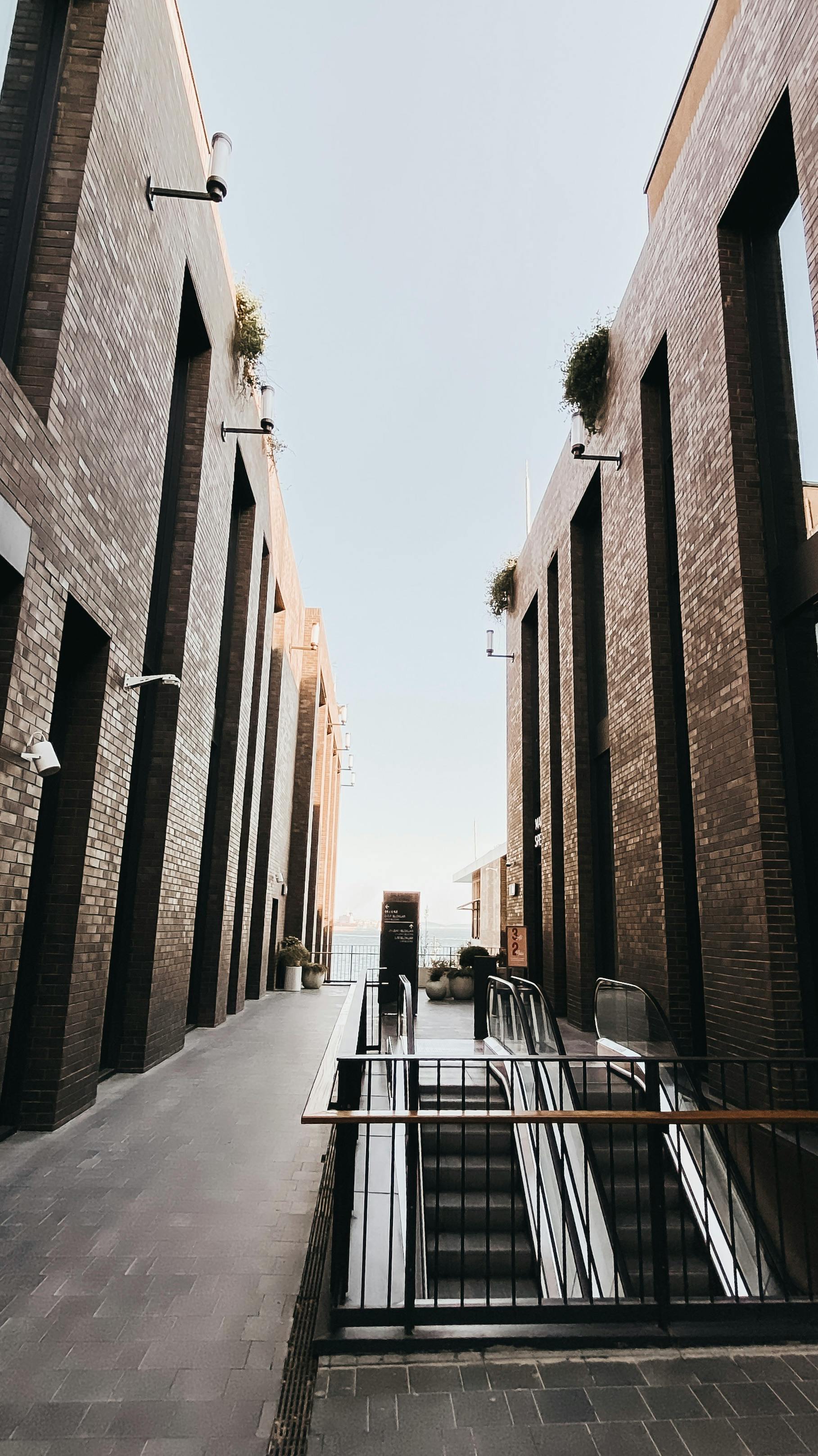 An Escalator Near Brown Brick Building · Free Stock Photo