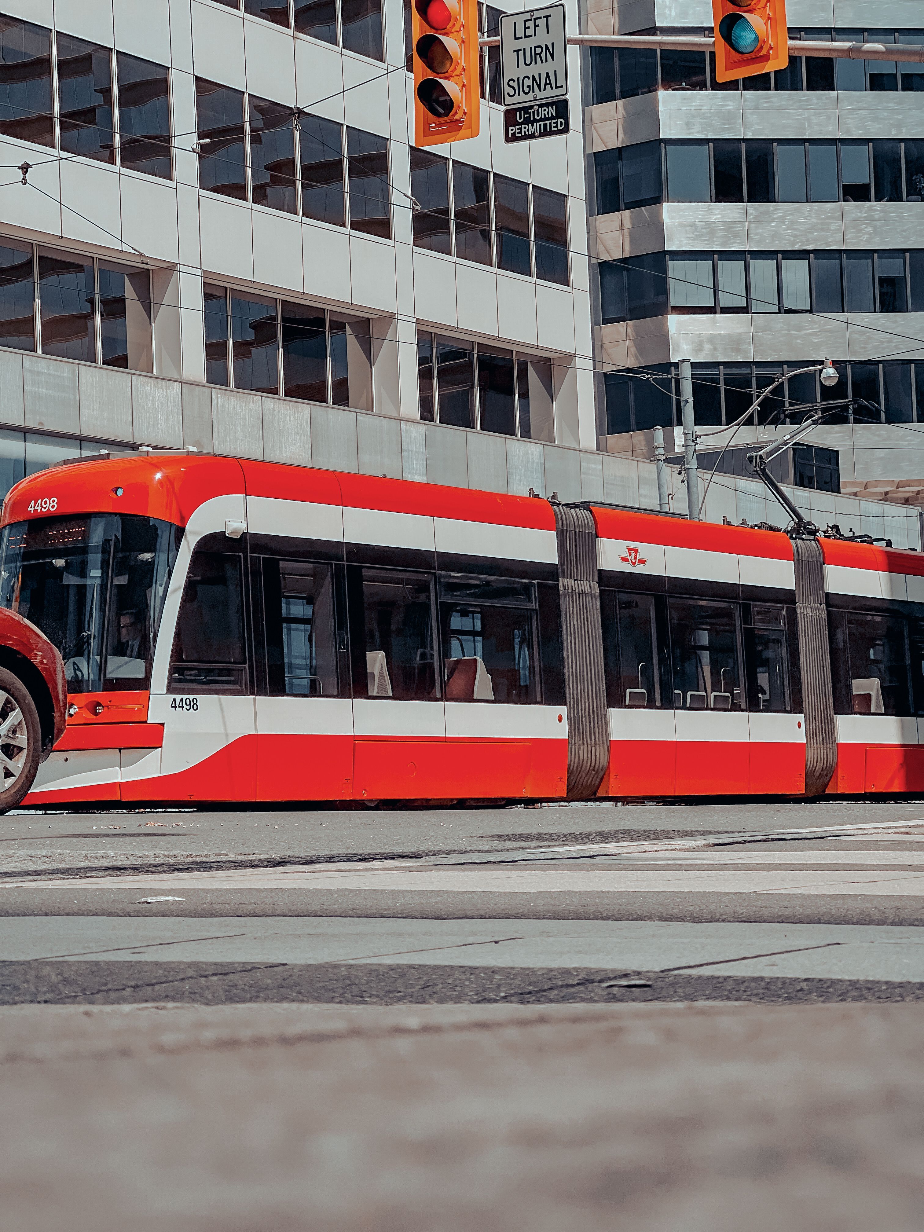 A Tram Passing Parked Vehicles and Buildings · Free Stock Photo