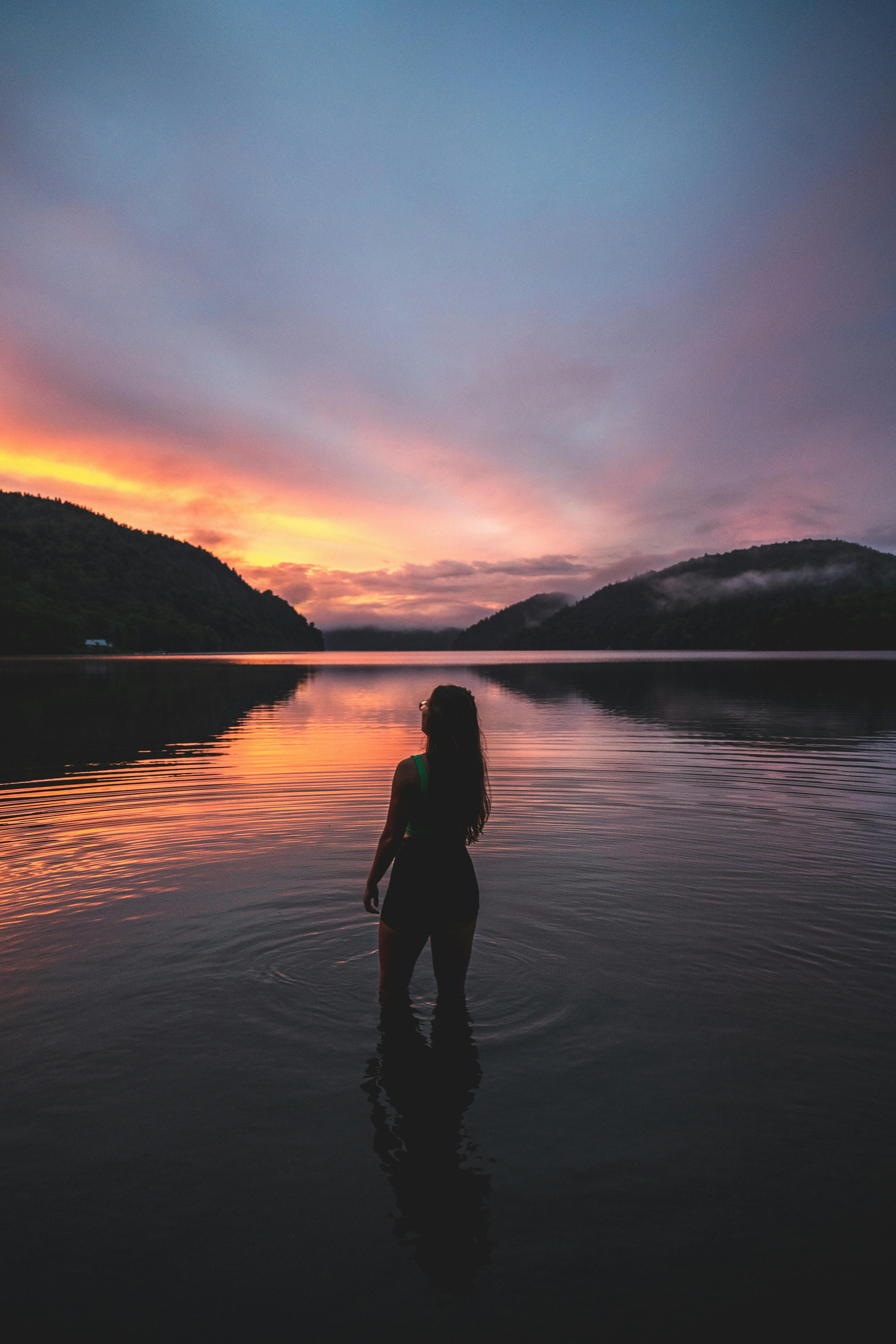 Woman Standing Knee Deep in Water at Sunset · Free Stock Photo