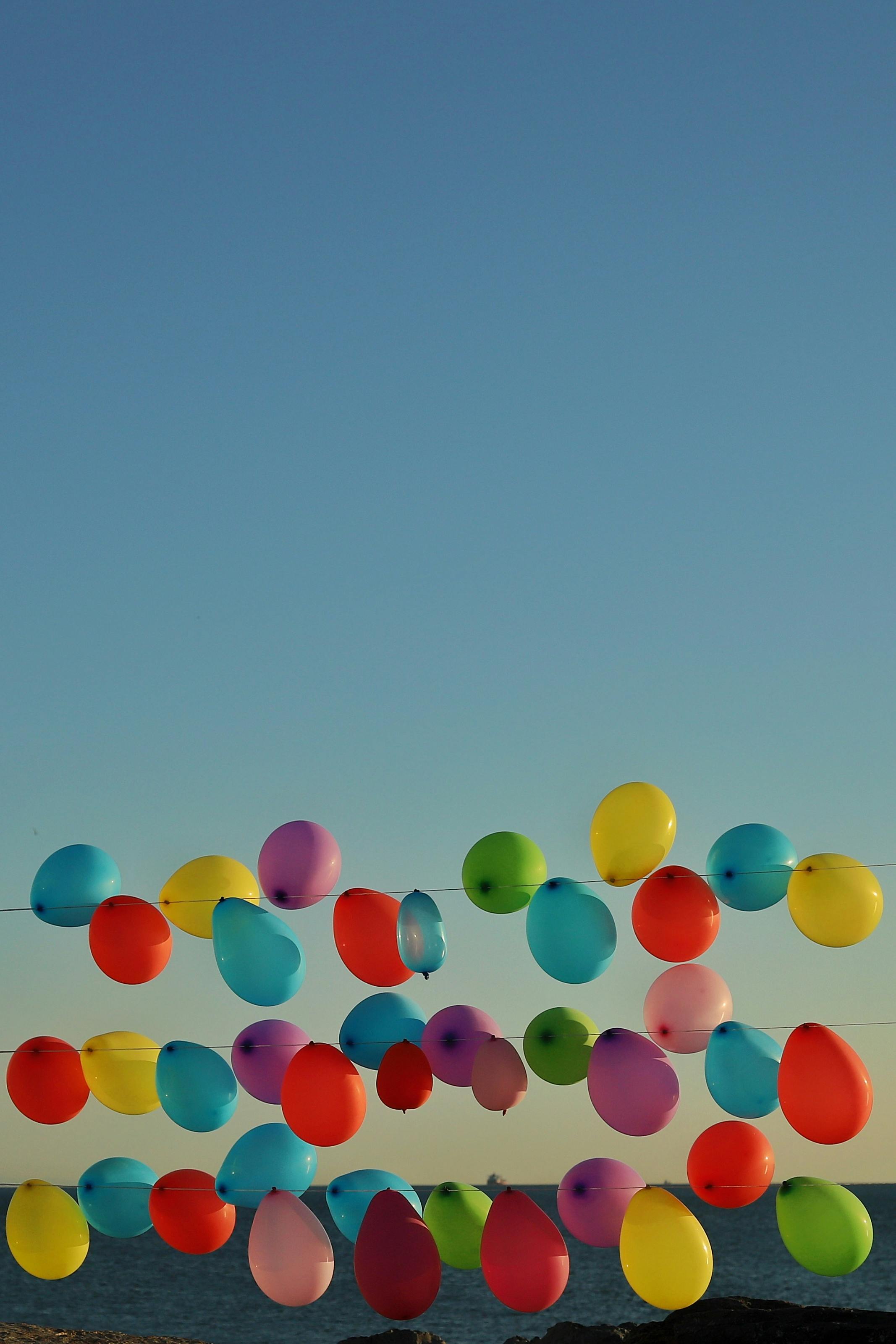 Colorful Balloons on String against Clear Sky · Free Stock Photo
