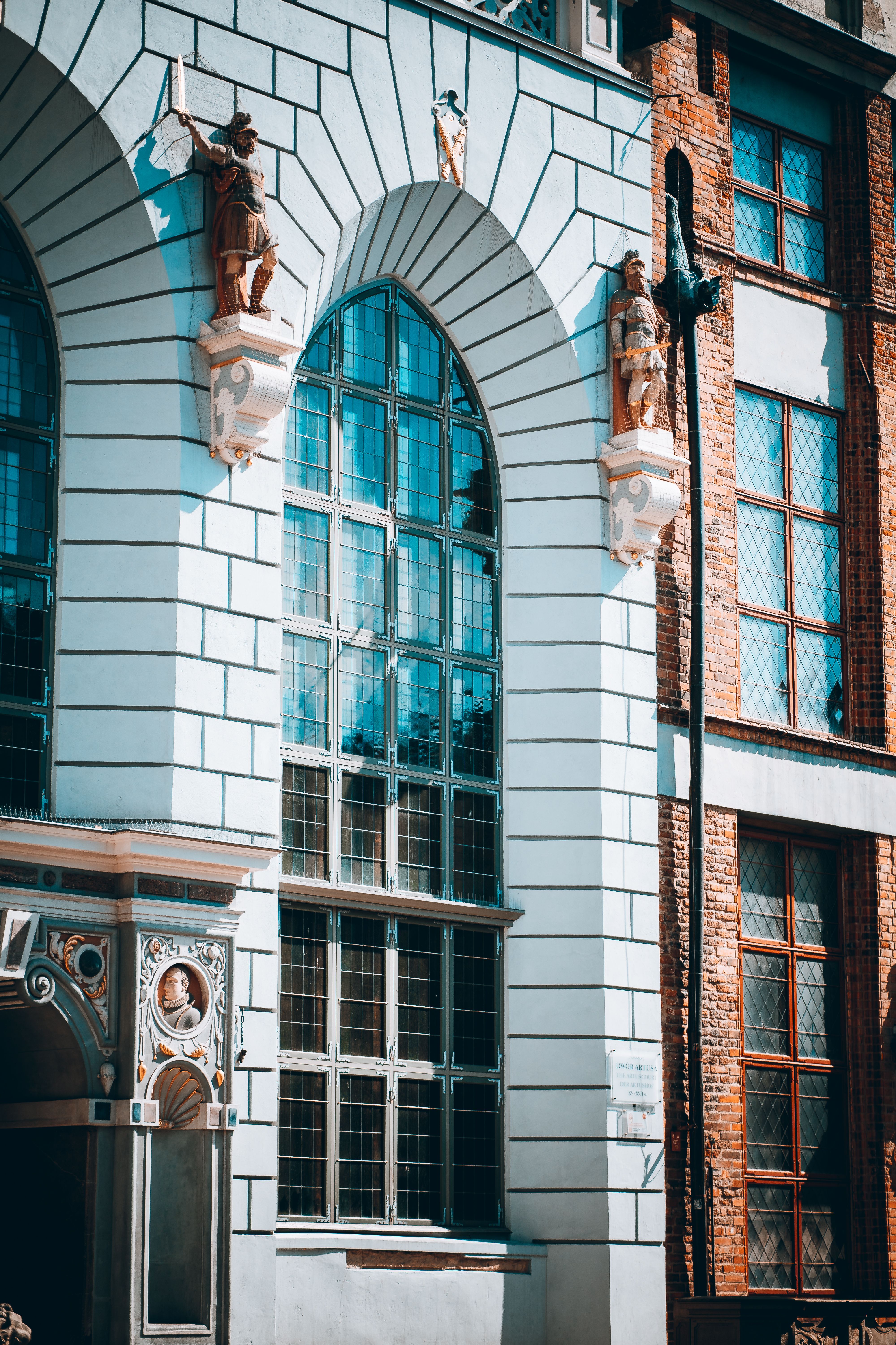 Statues on Concrete Walls Beside Arched Windows · Free Stock Photo
