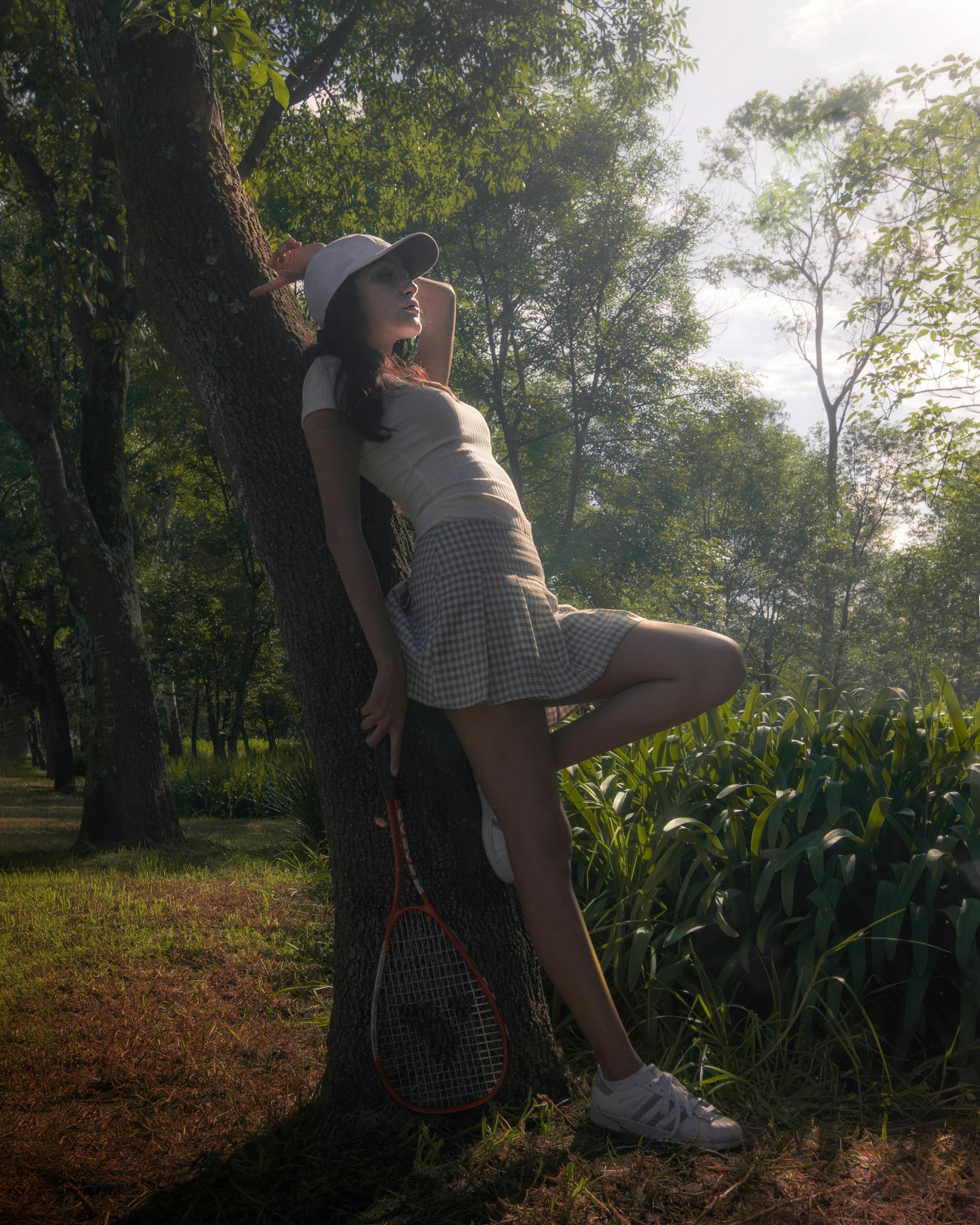 Woman Holding Tennis Racket Leaning on Tree Trunk · Free Stock Photo