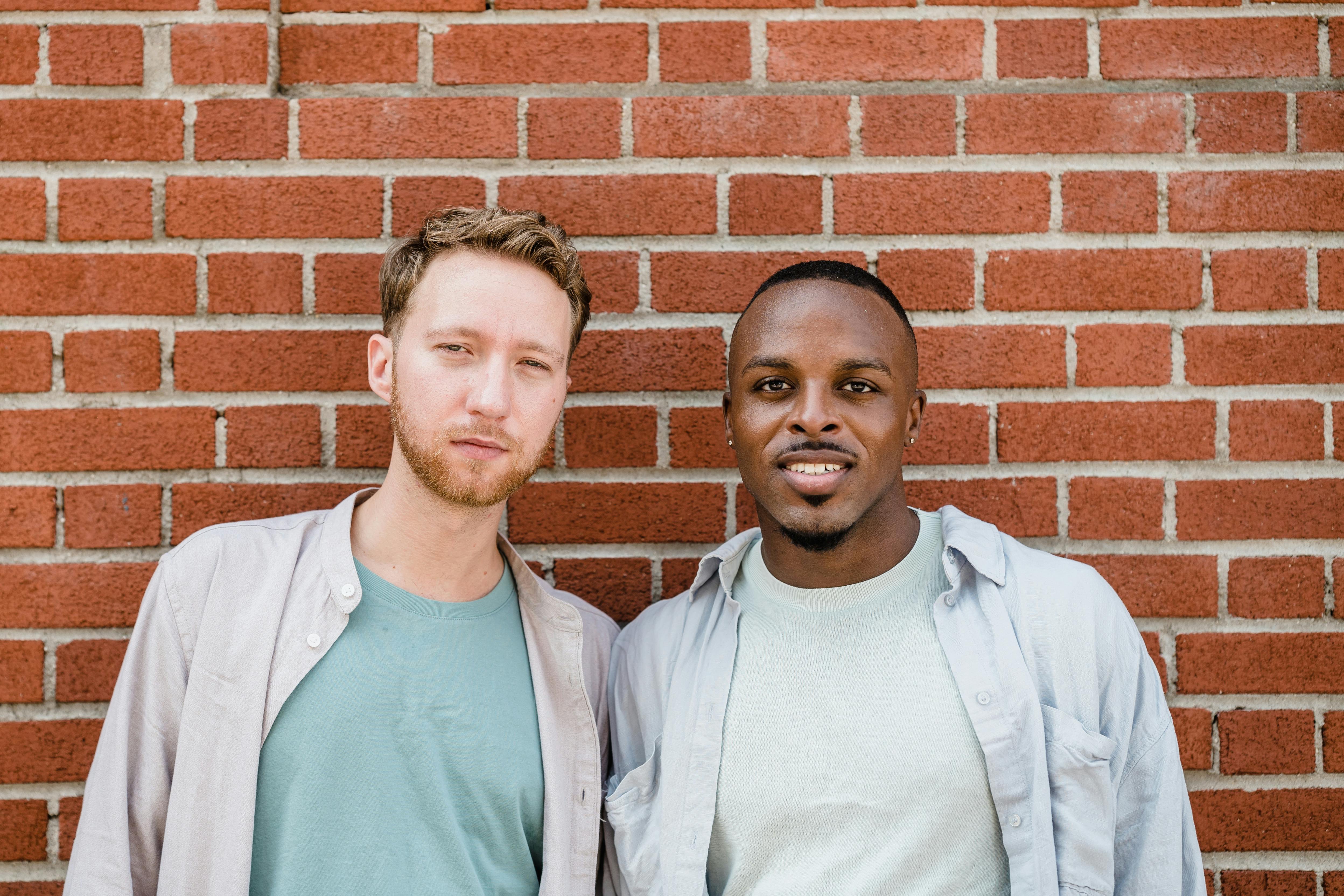 Portrait of Two Men against a Brick Wall · Free Stock Photo
